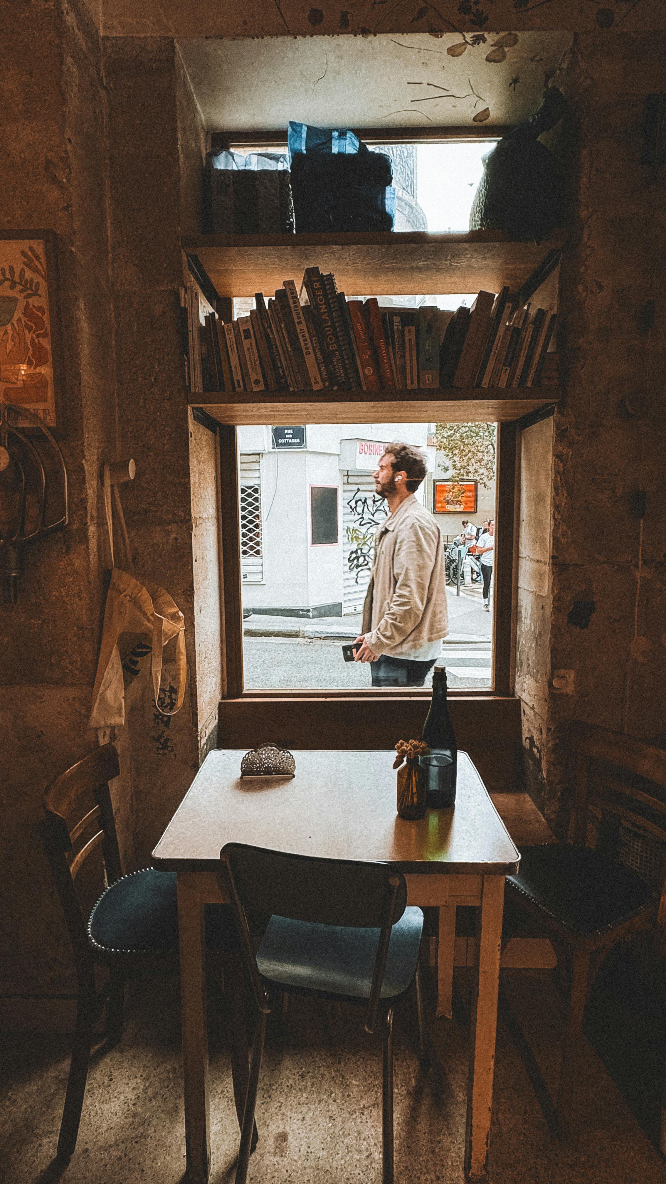 Cozy Parisian Cafe Window View with Books · Free Stock Photo