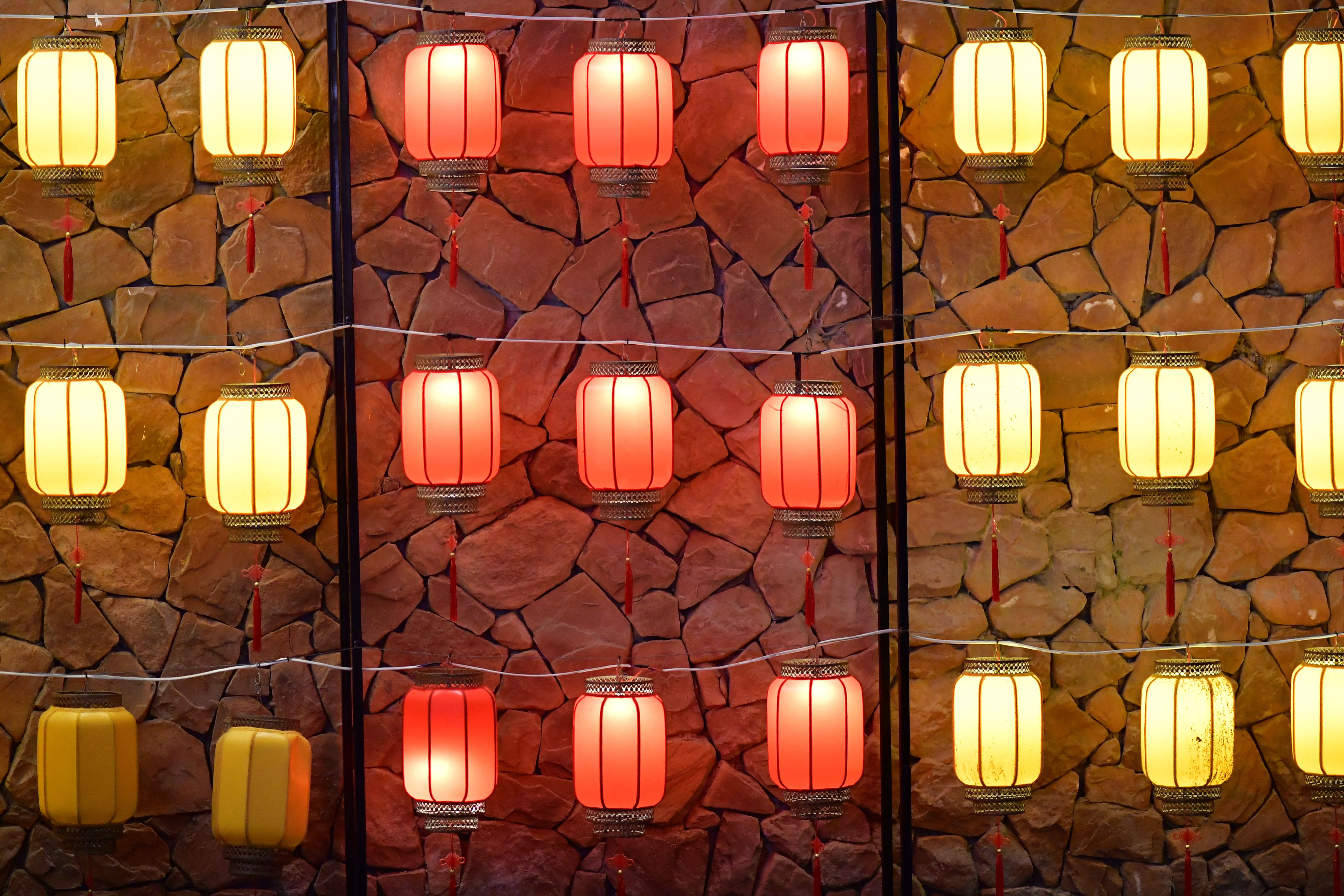 Vibrant Red and Yellow Lanterns on Stone Wall · Free Stock Photo