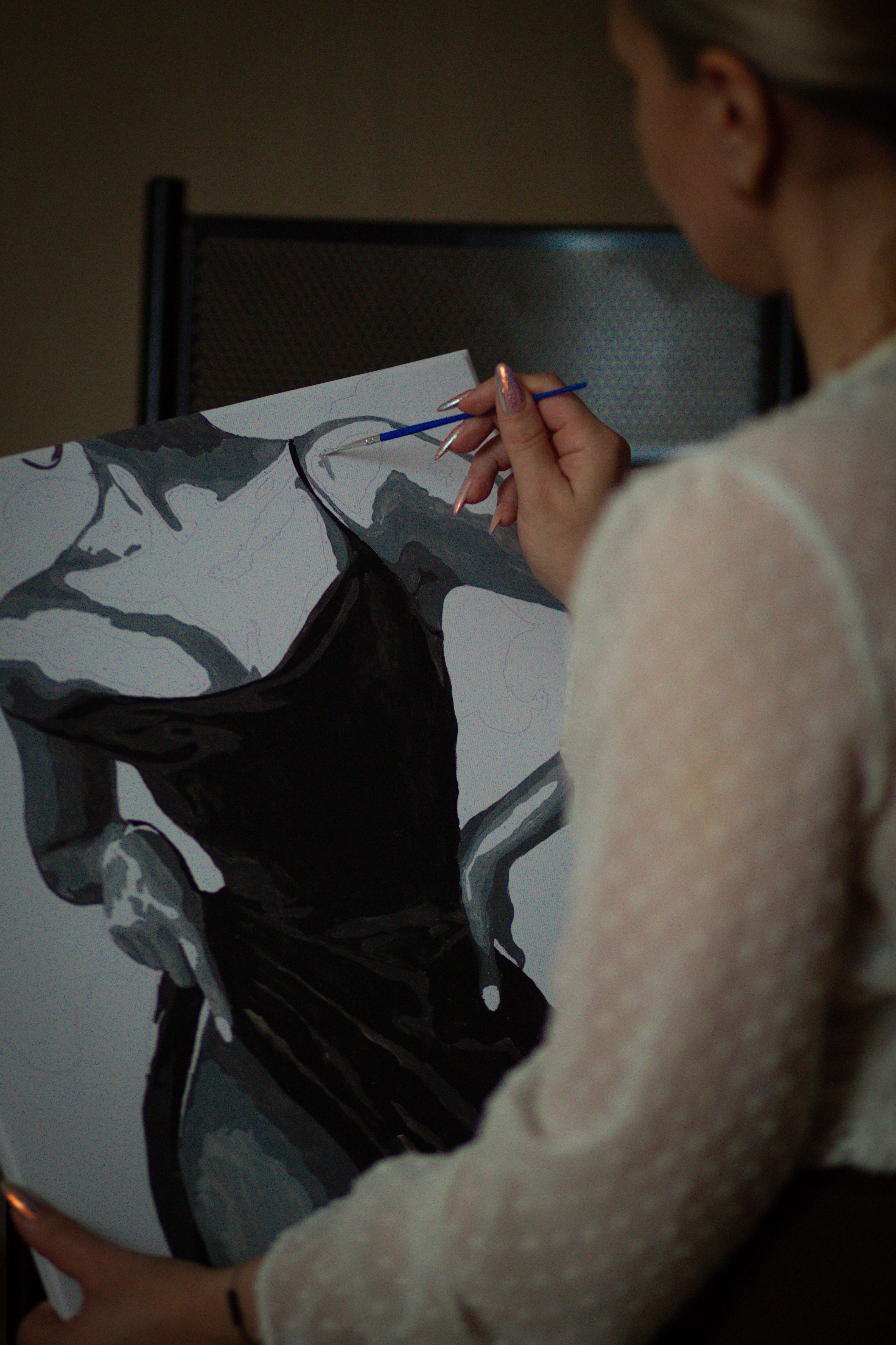 Woman painting a monochrome figure on canvas · Free Stock Photo