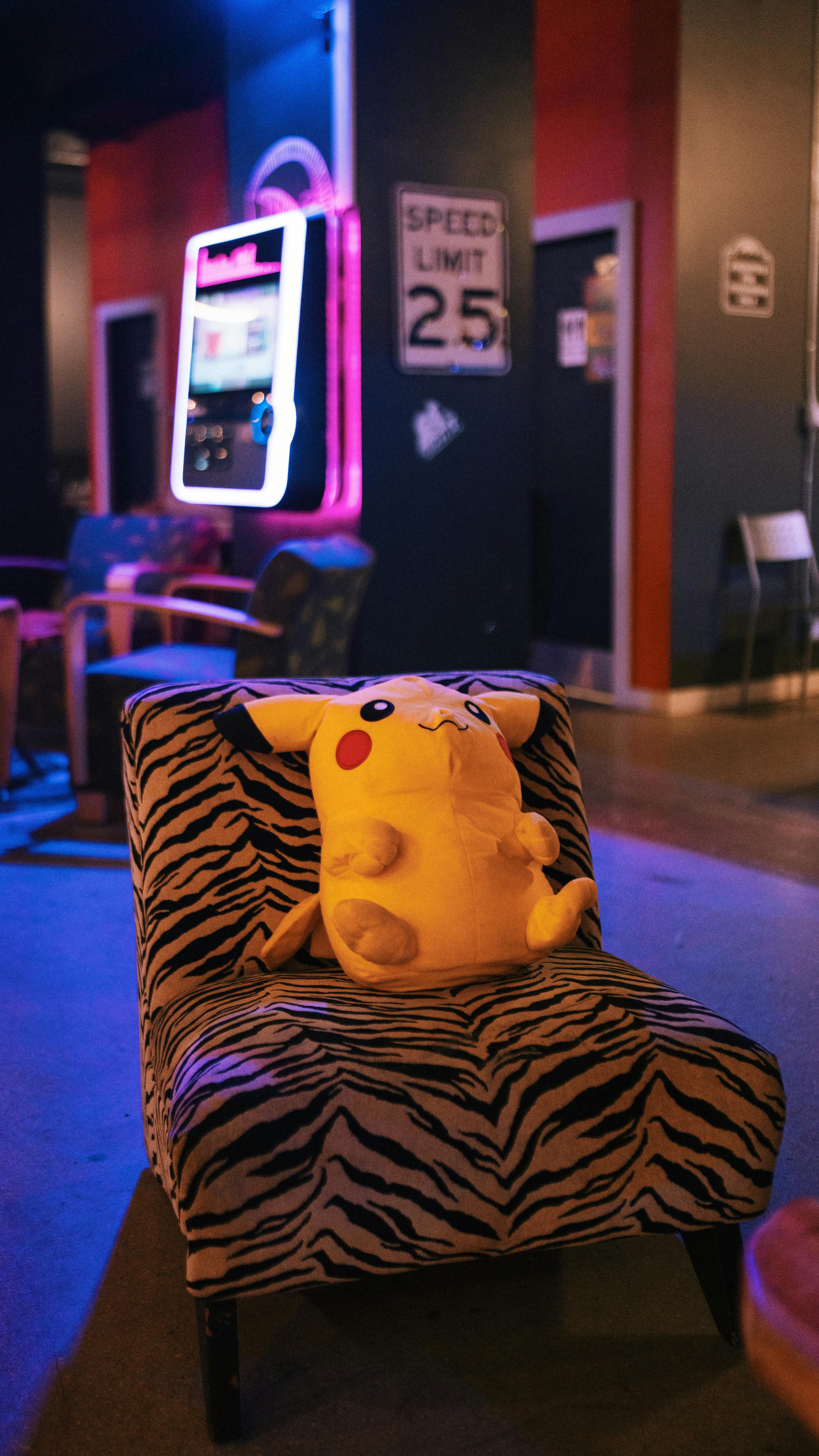 Pikachu Plush on Zebra Print Chair in Neon Lounge · Free Stock Photo