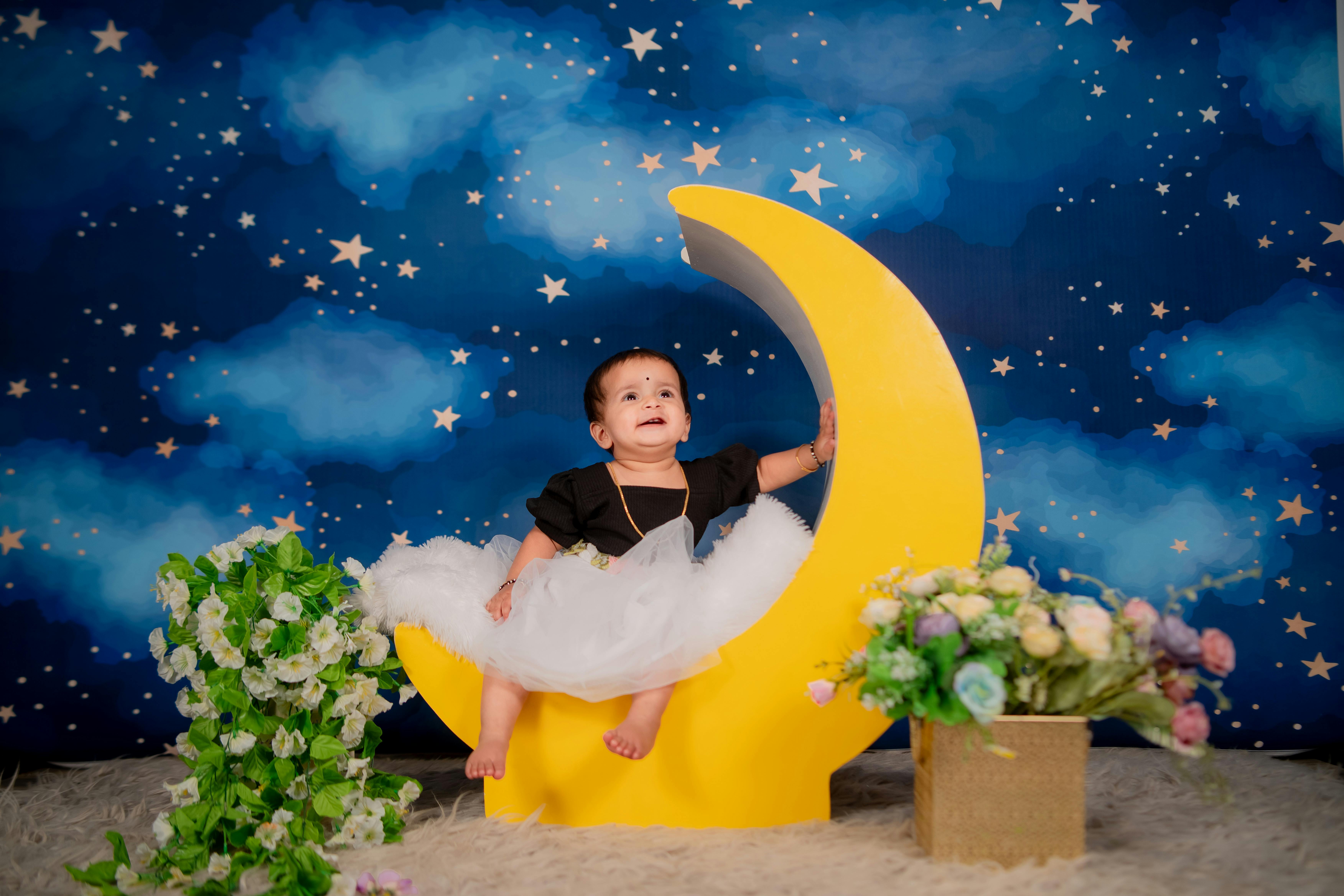 Adorable Baby on Moon Prop in Starry Setting · Free Stock Photo