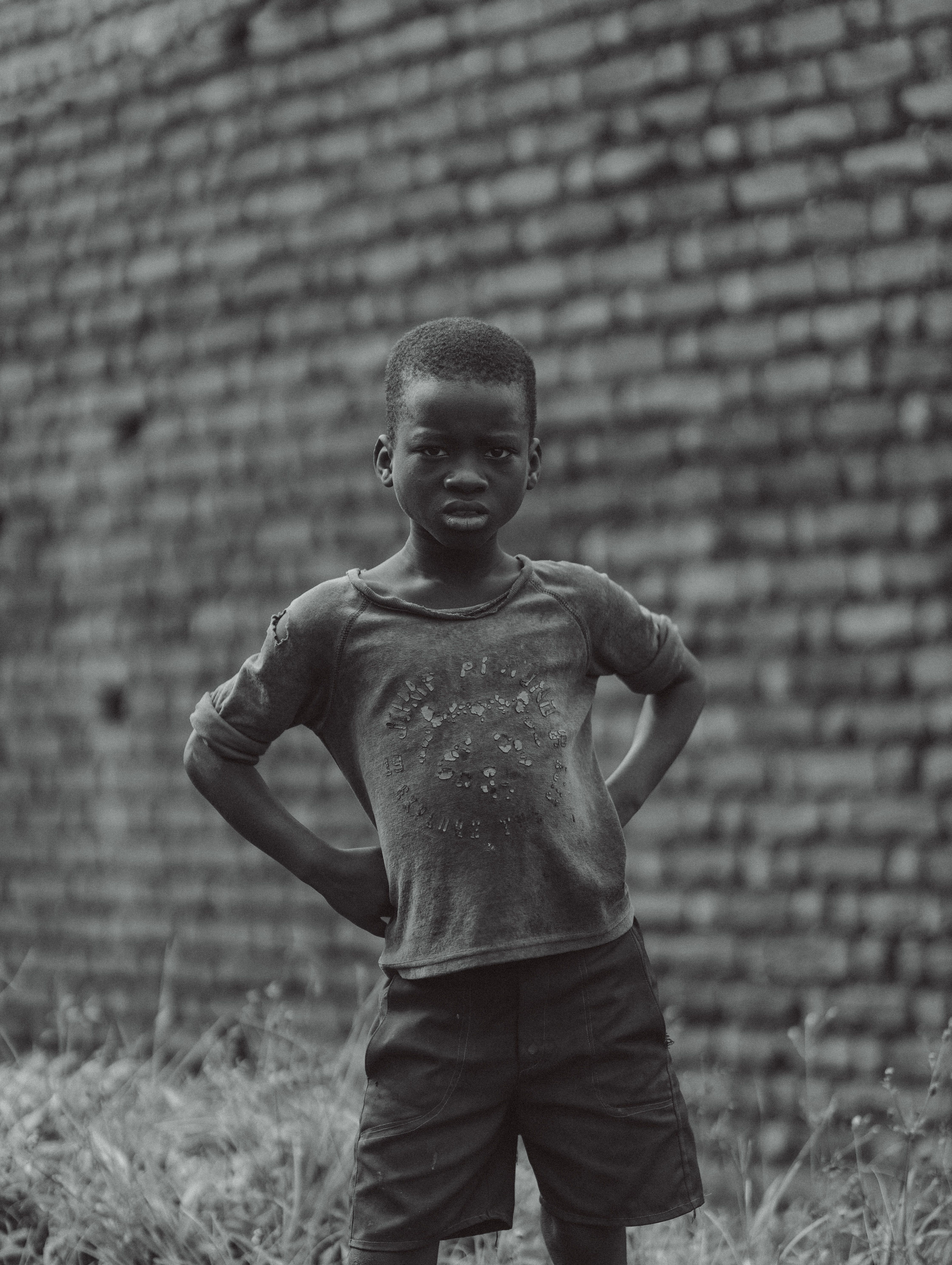 Confident Child Posing Against Brick Wall · Free Stock Photo