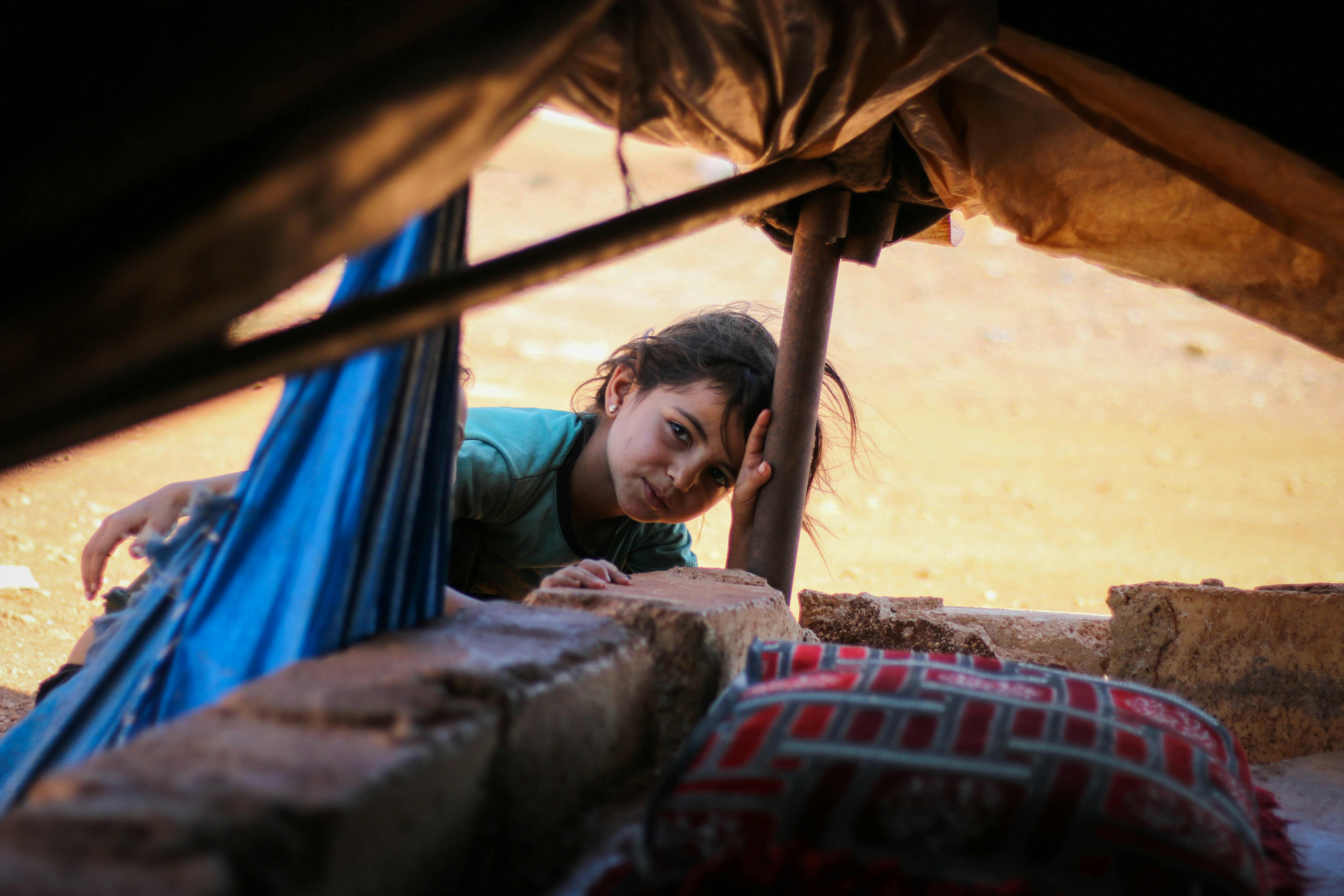 Young Girl Peeking Outside Tent in Idlib Camp · Free Stock Photo