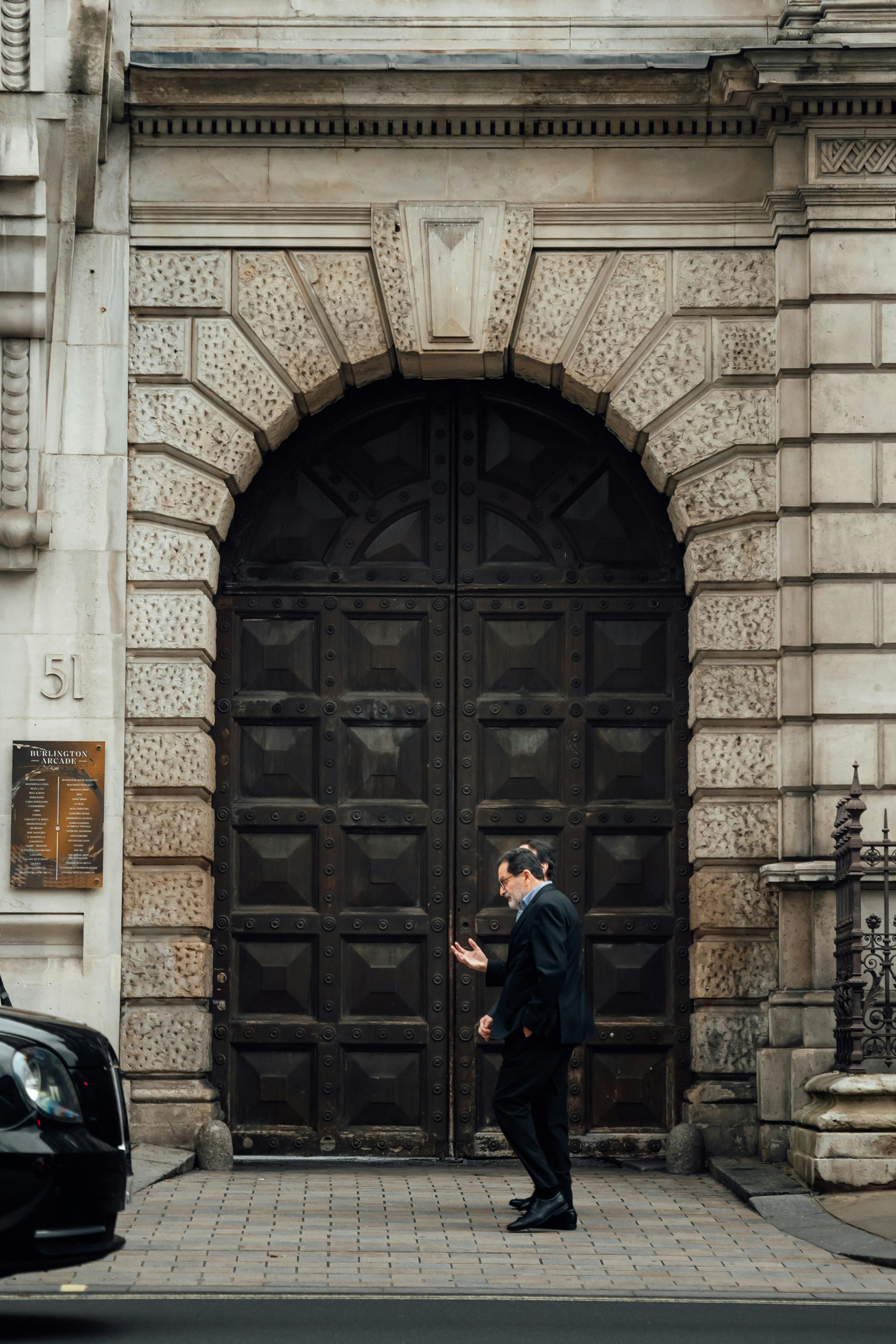 Businessman Walking in Front of Historic London Gate · Free Stock Photo