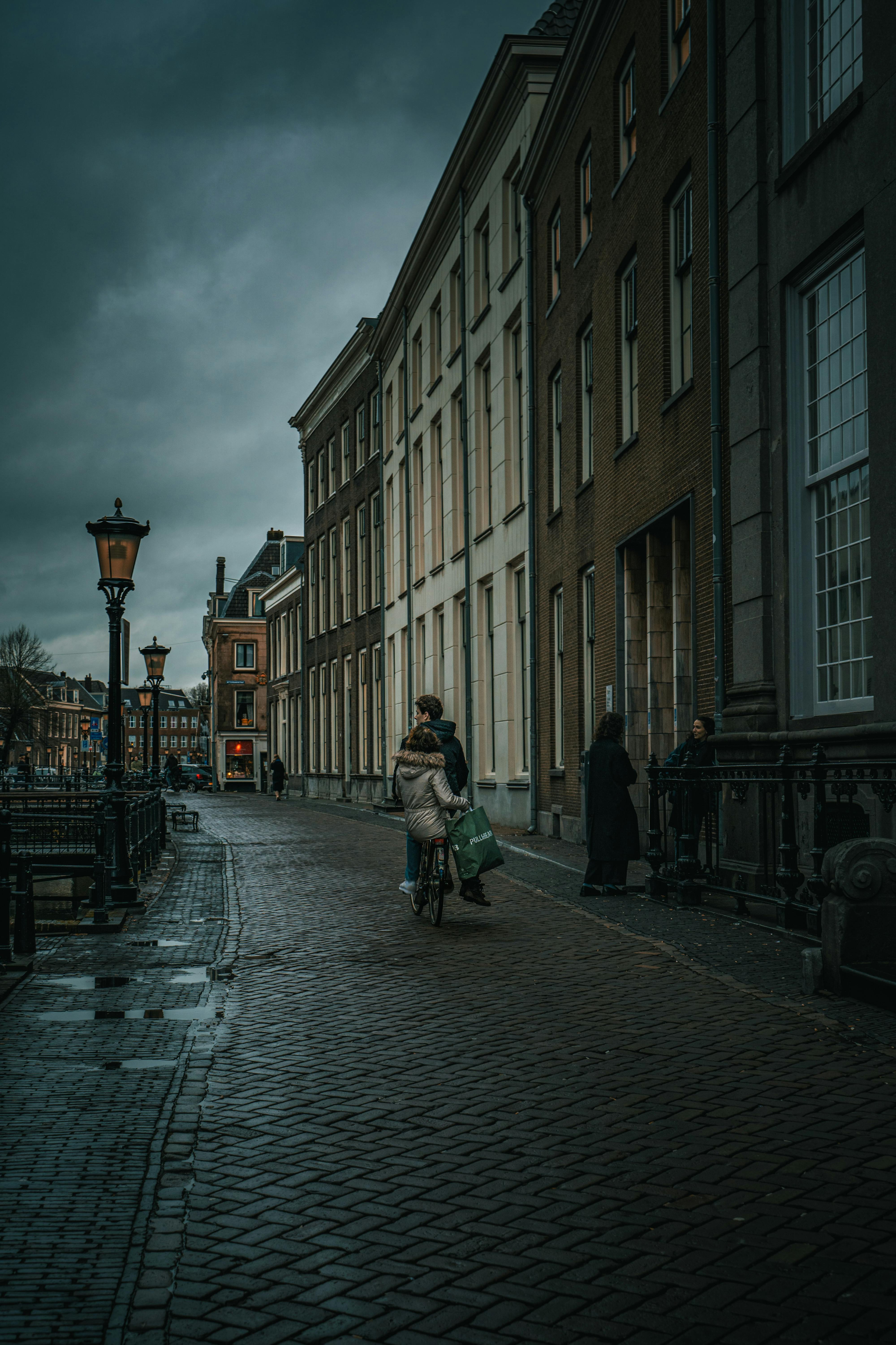 Couple Cycling on a Cobblestone Street in Europe · Free Stock Photo