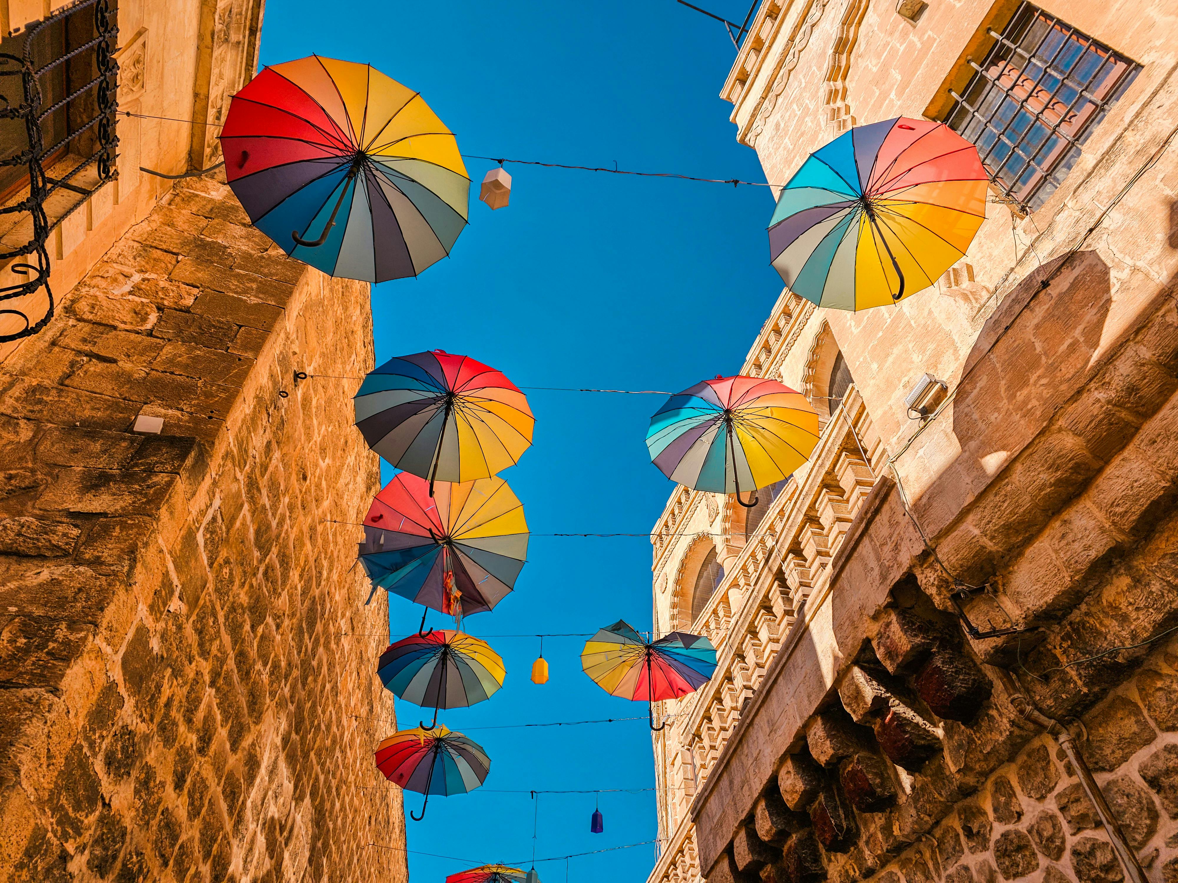 Colorful Umbrellas Between Historic Stone Buildings · Free Stock Photo