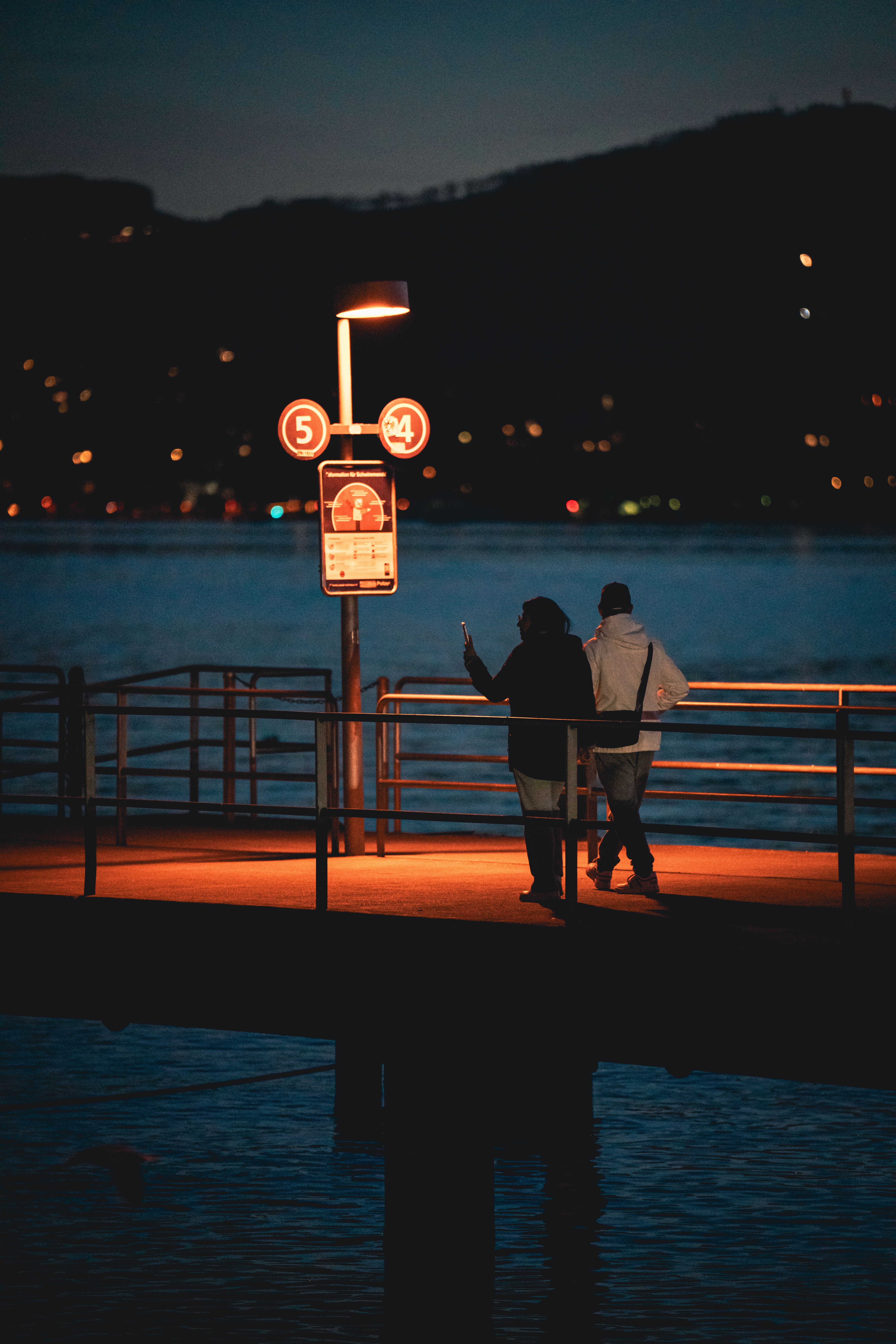Couple Walking on Pier at Night with City Lights · Free Stock Photo