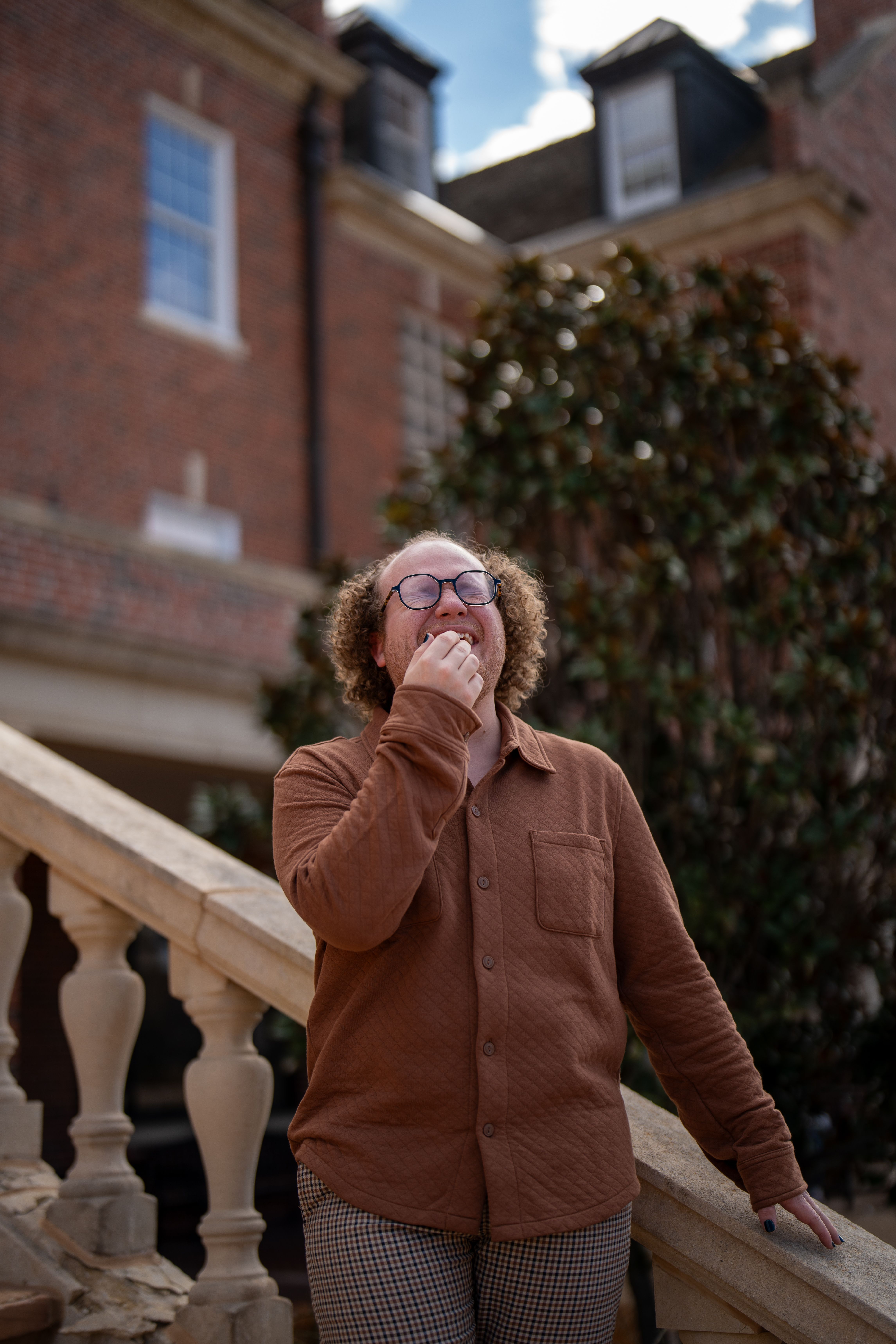 Stylish Man Laughing Outside Brick Building · Free Stock Photo