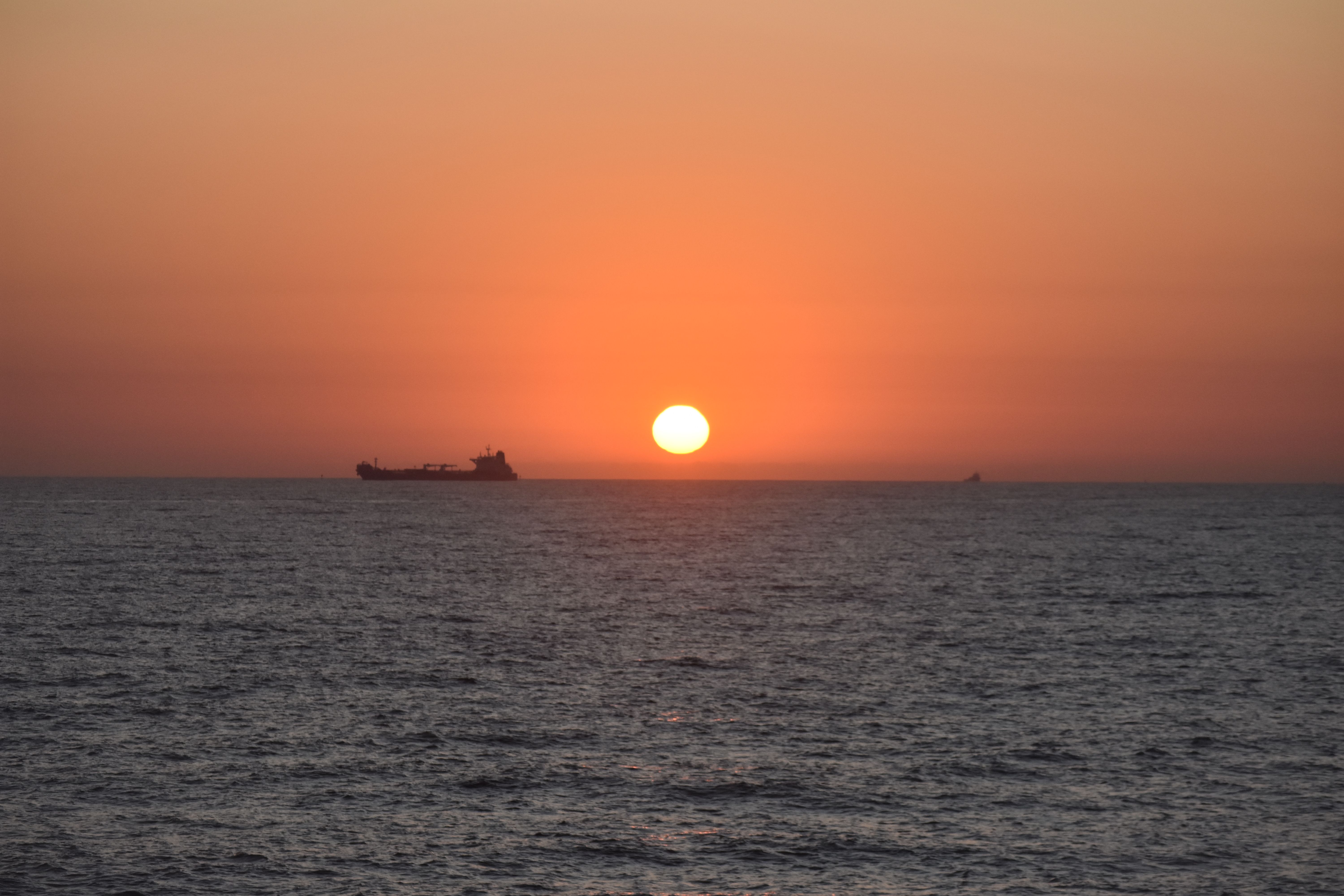 Serene Ocean Sunset with Ship Silhouette · Free Stock Photo