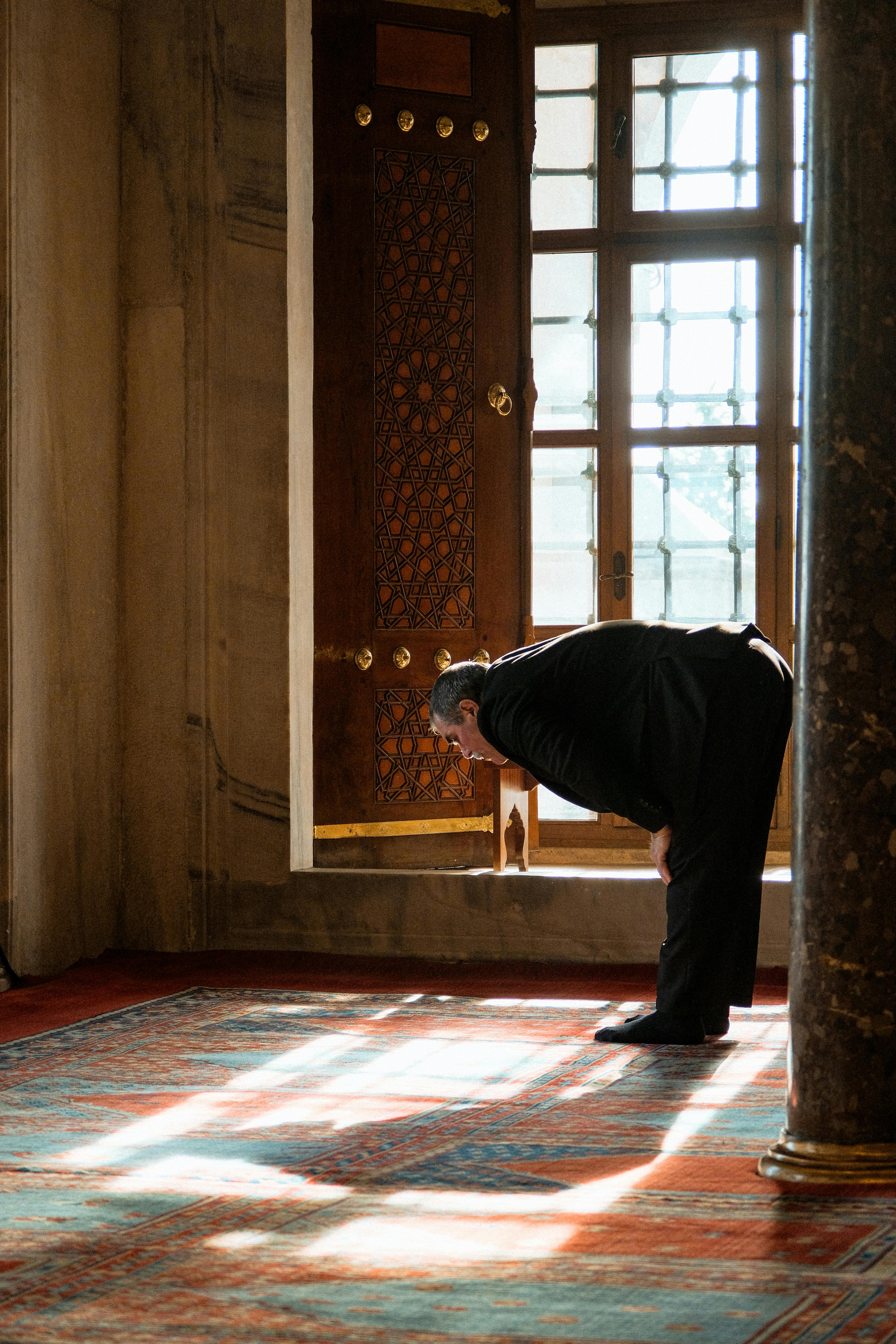 Man Bowing in Sunlit Mosque Interior · Free Stock Photo