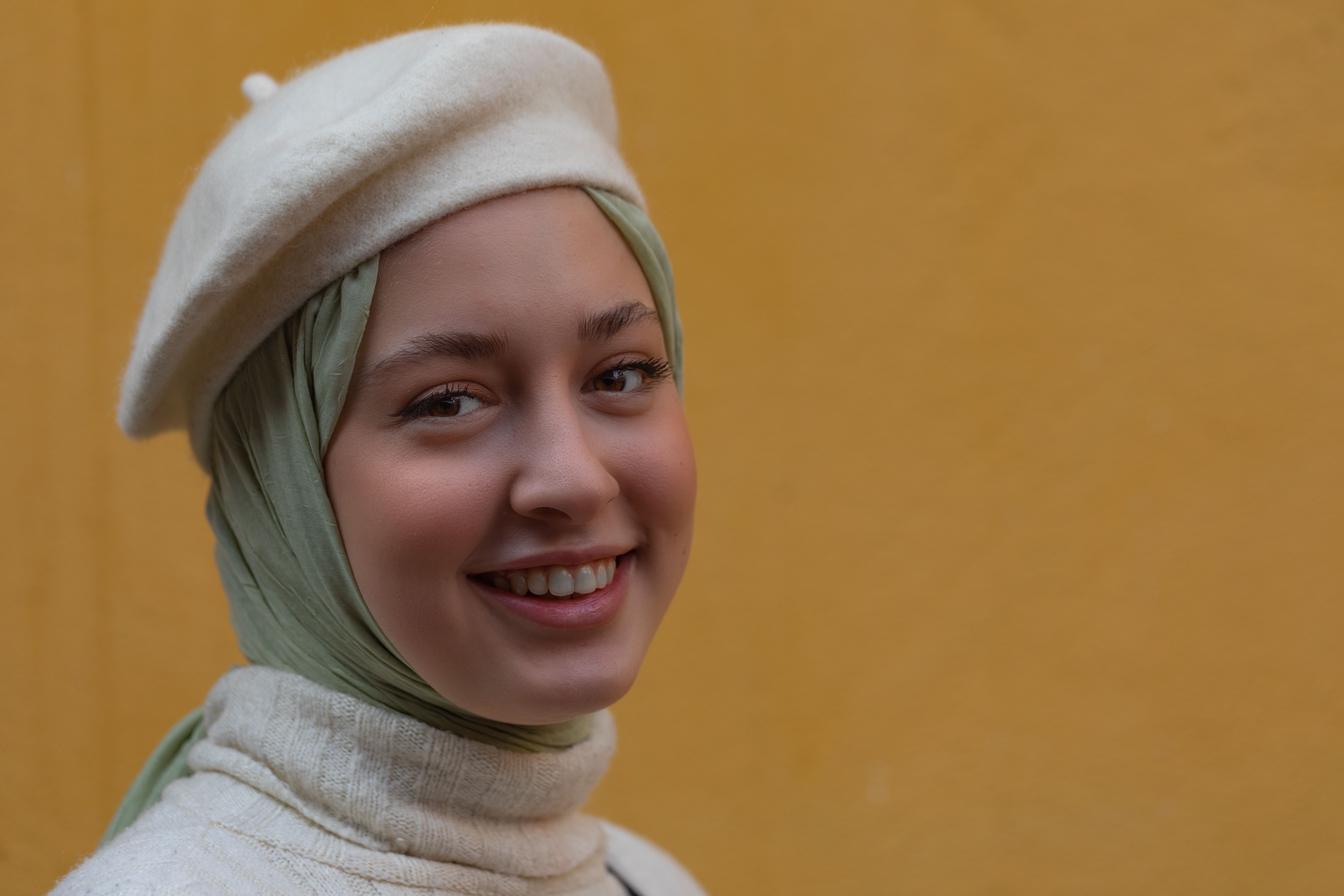 Smiling Woman in Beret and Hijab Against Yellow Wall · Free Stock Photo