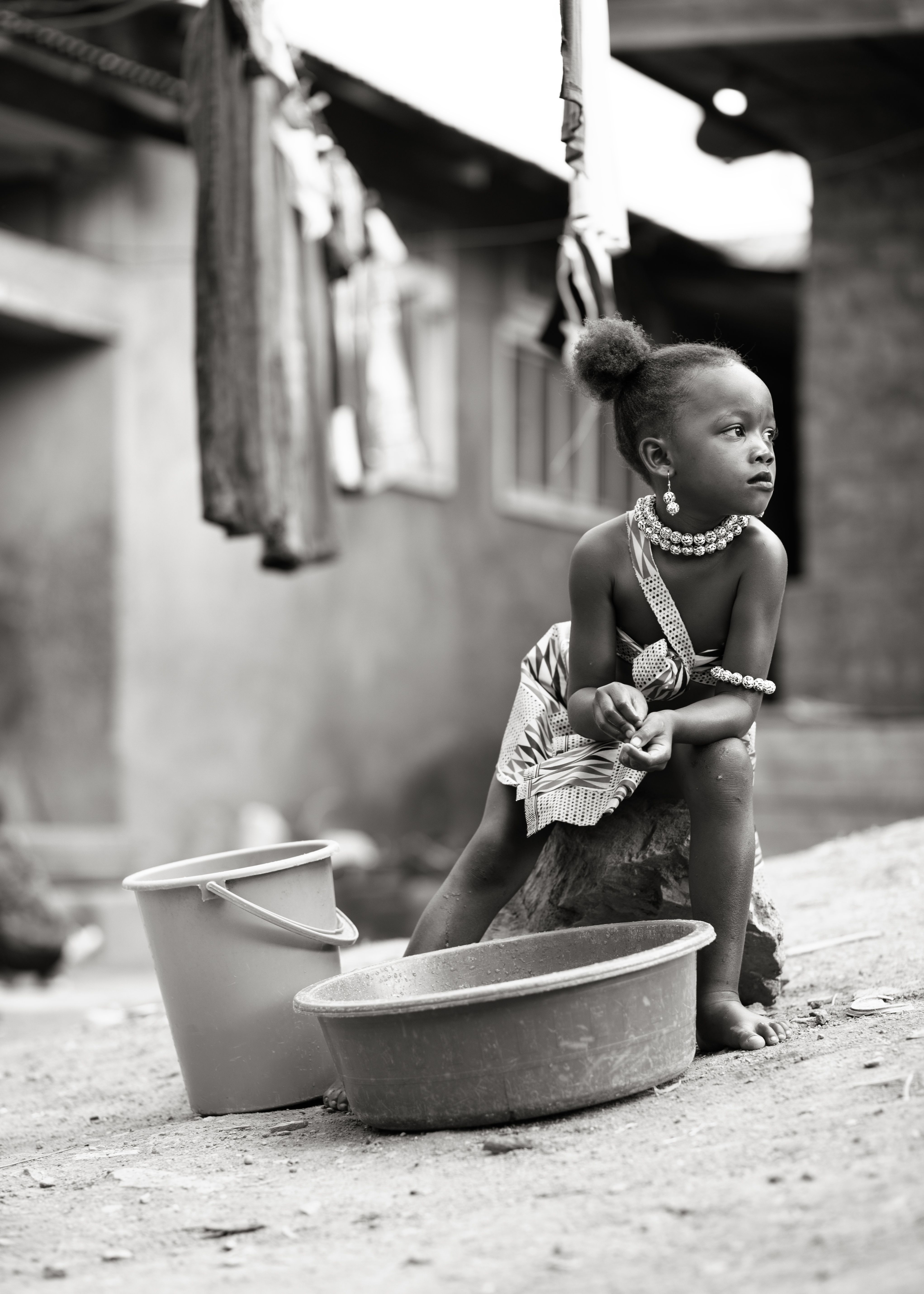 Young Girl Sitting with Buckets in Outdoor Setting · Free Stock Photo