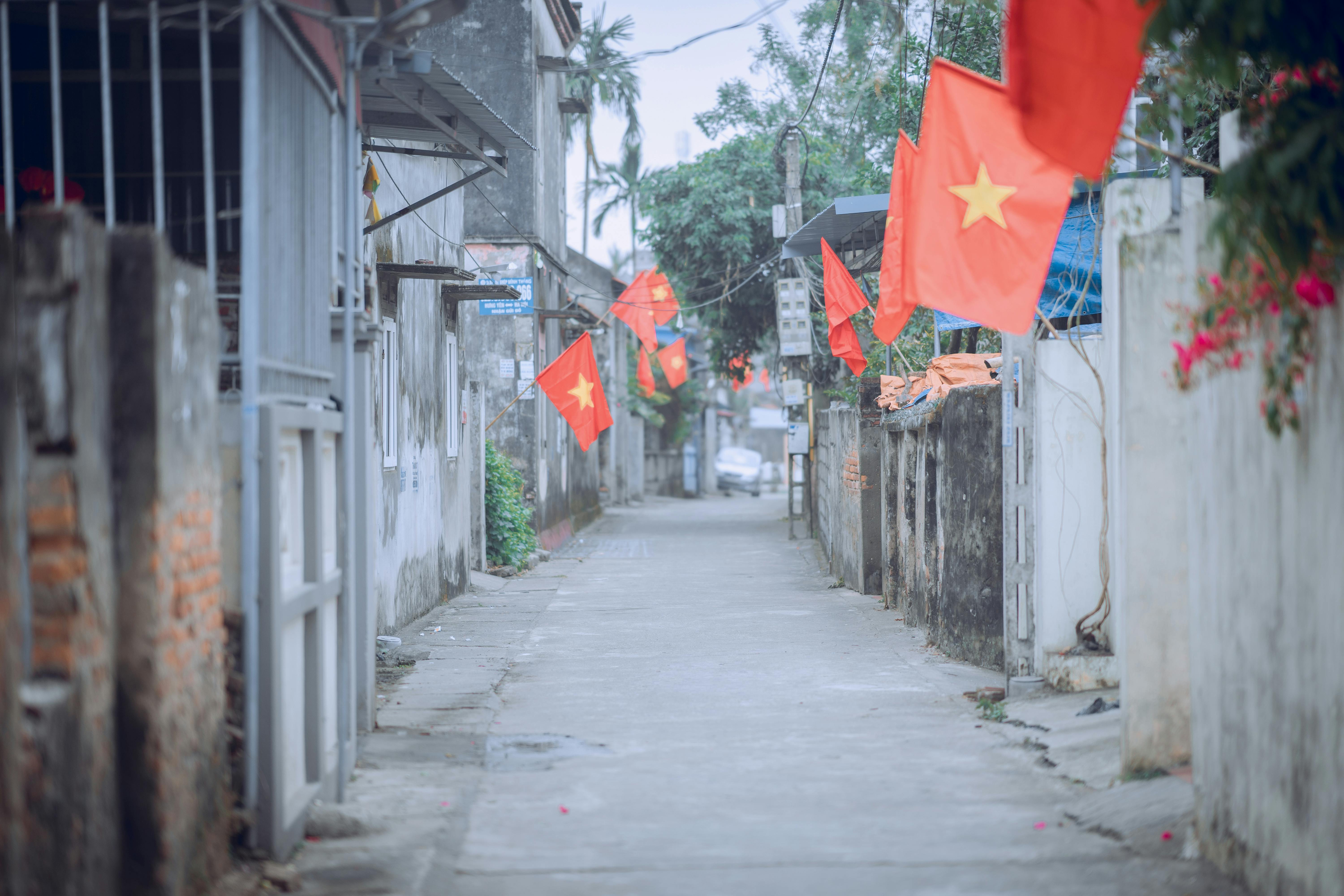 Quiet Vietnamese street adorned with flags · Free Stock Photo