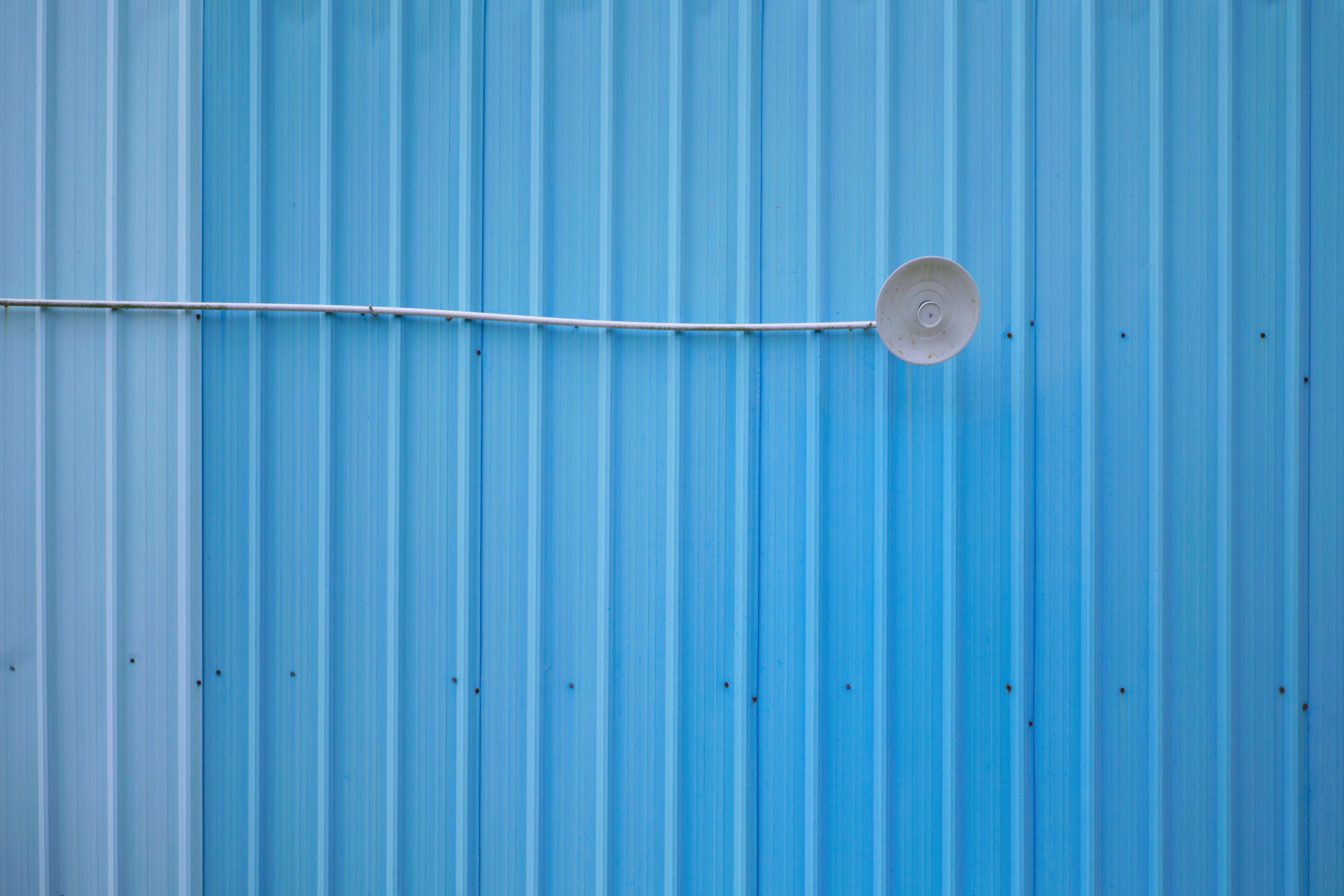 Minimalist Blue Metal Wall with Disc Antenna · Free Stock Photo