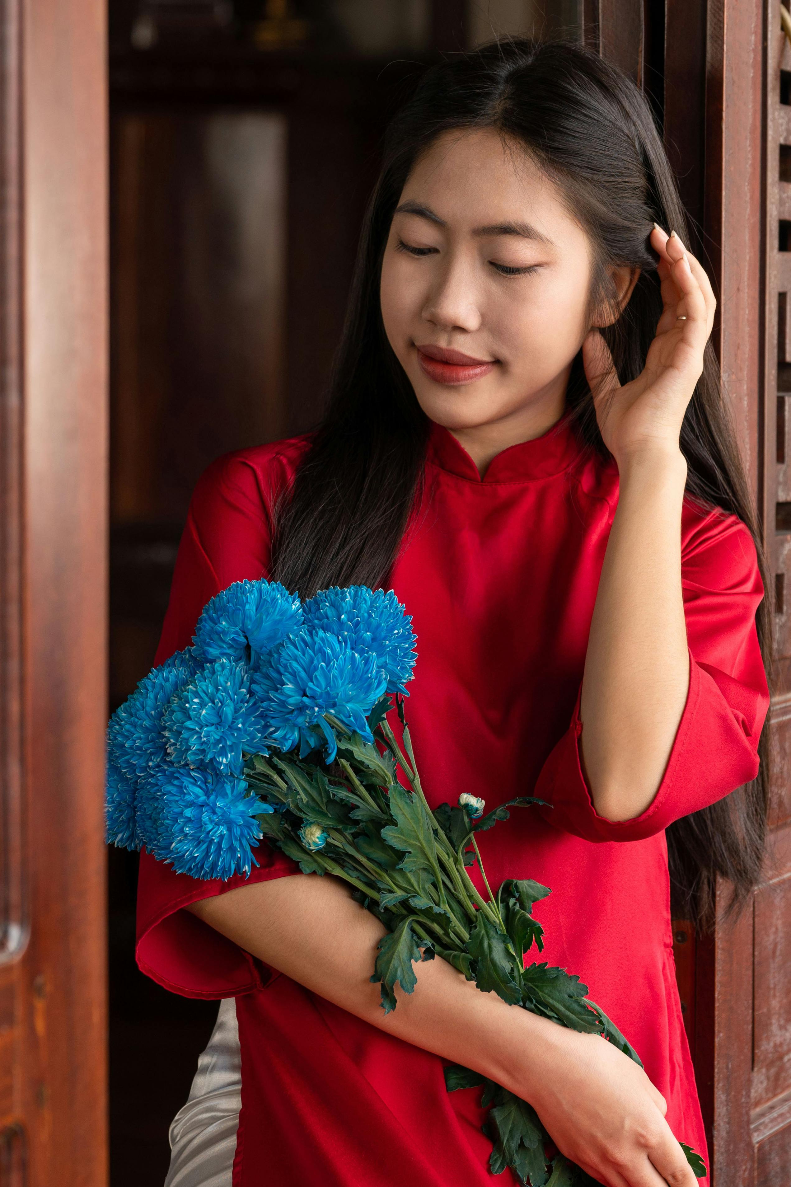 Woman in Red Dress Holding Blue Flowers Indoors · Free Stock Photo