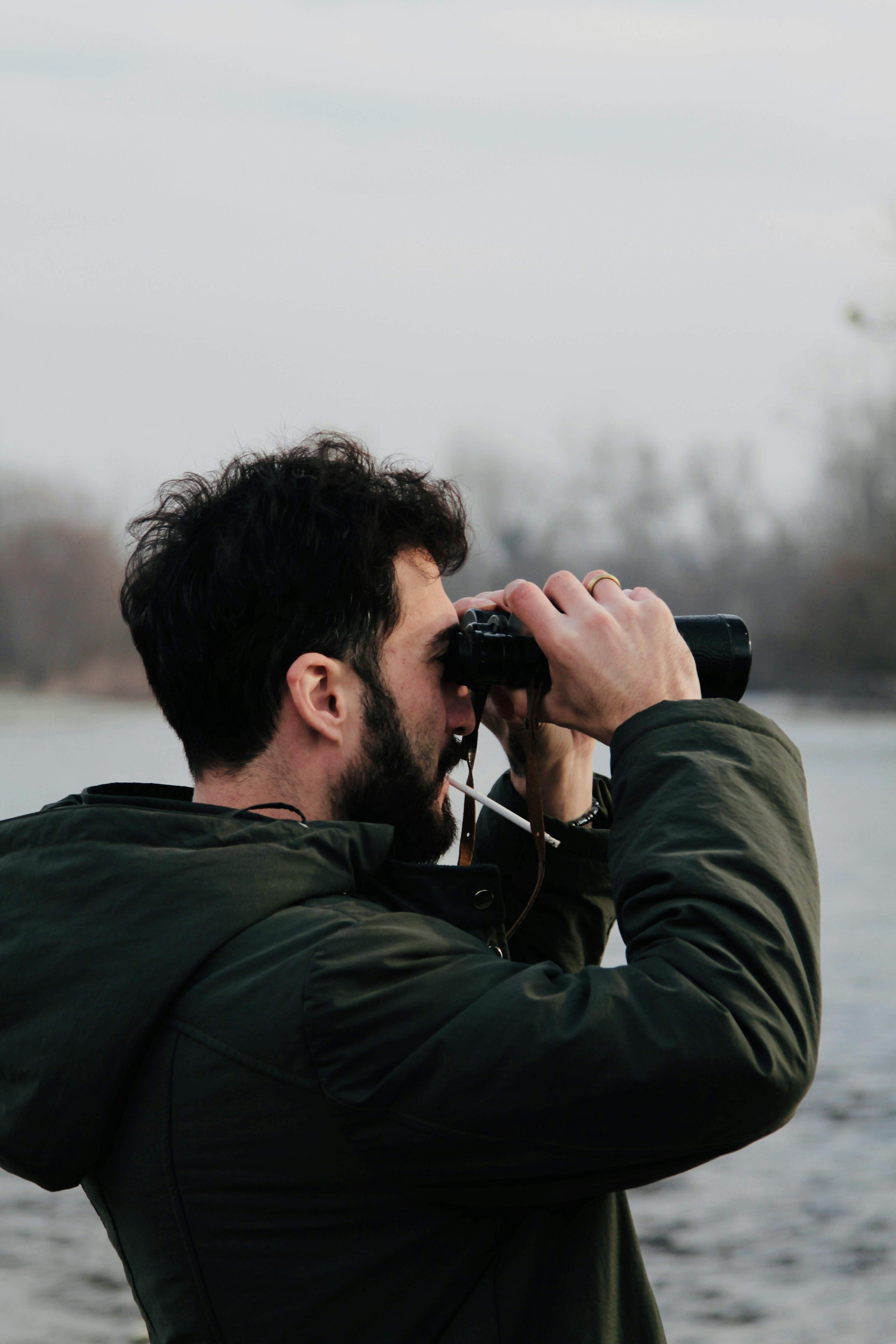 Man Observing Nature with Binoculars Outdoors · Free Stock Photo