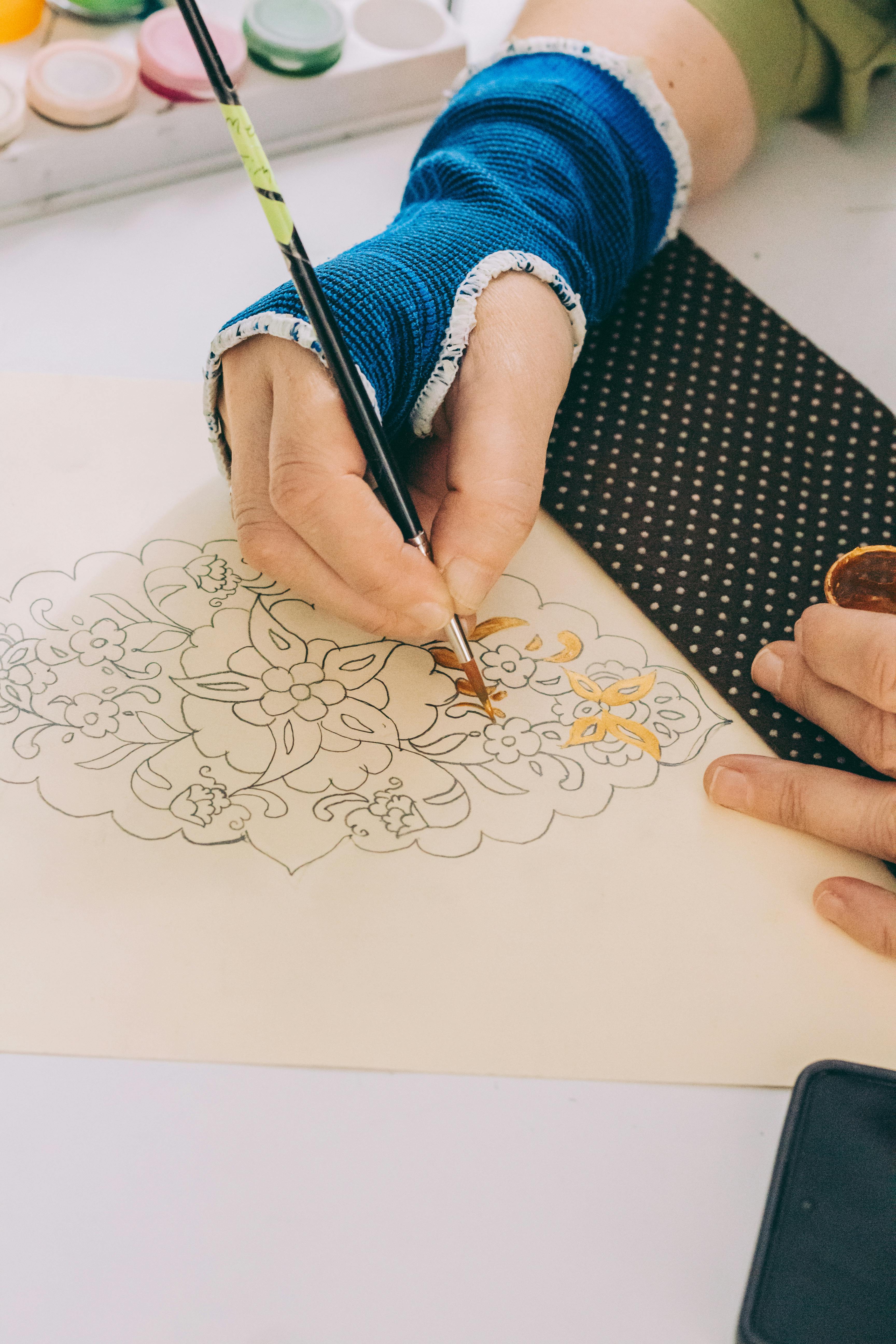 Person with blue cast painting intricate floral design · Free Stock Photo