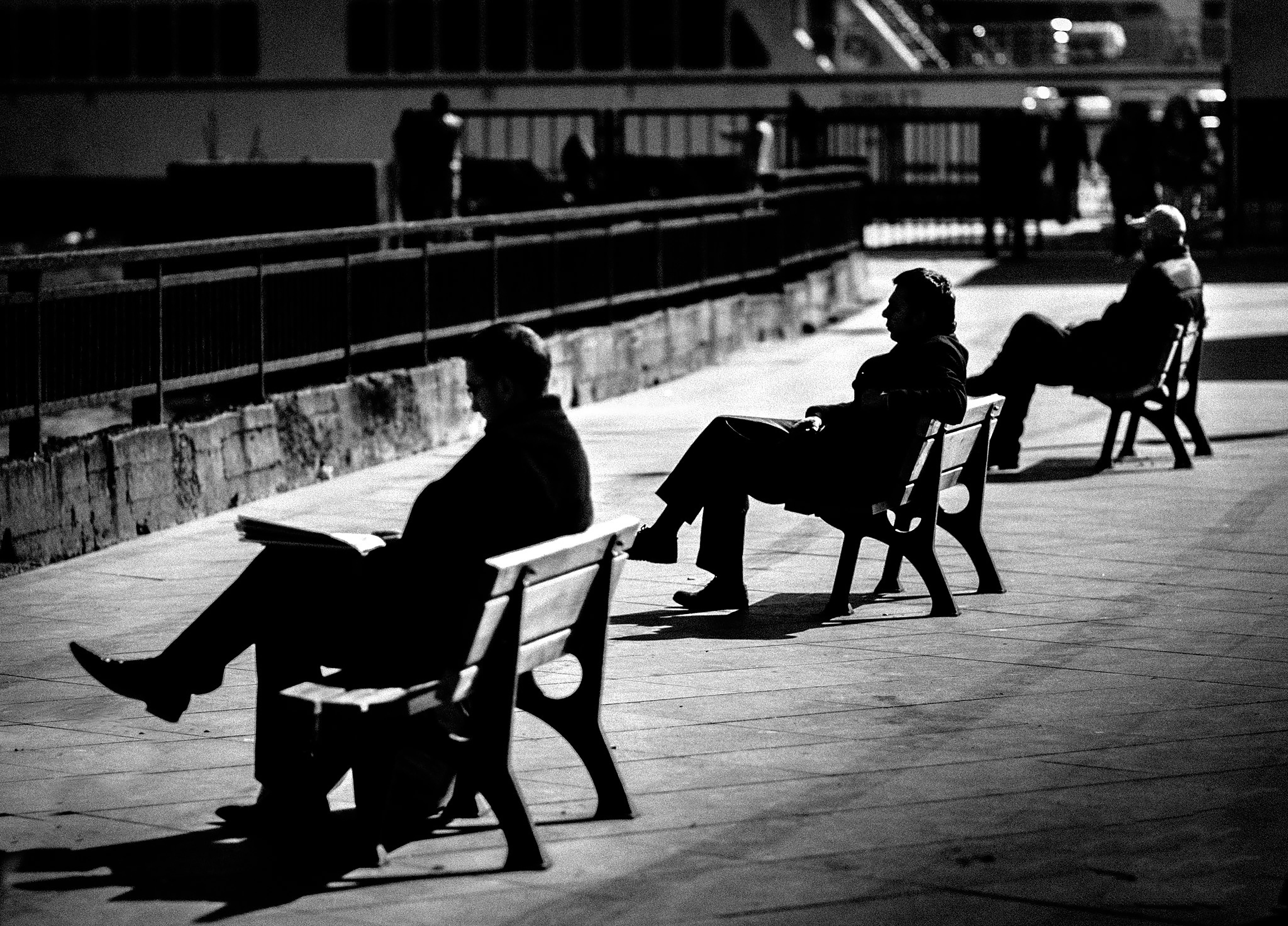 Silhouetted figures resting on urban benches · Free Stock Photo