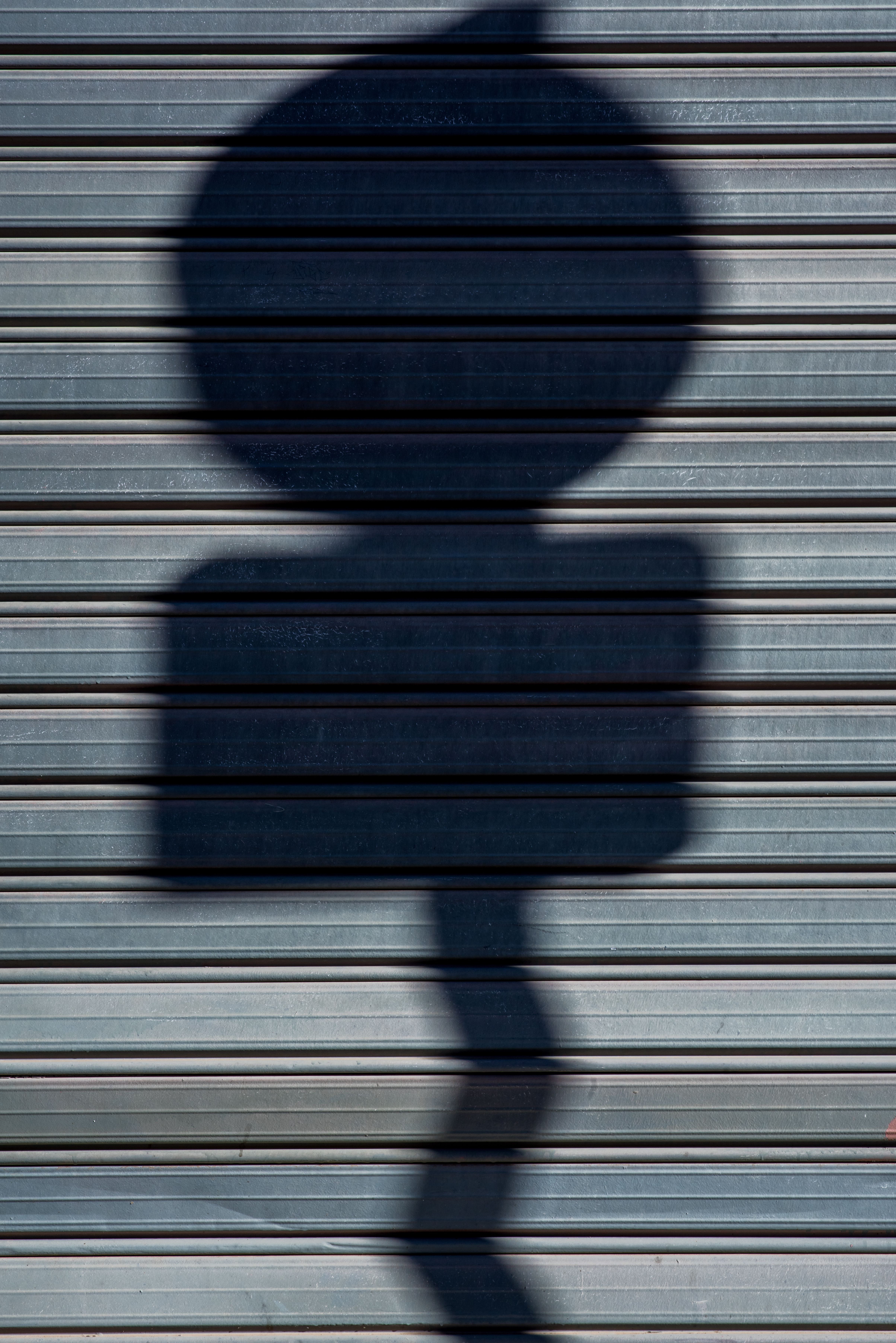 Shadow of a Sign Cast on Metal Shutter · Free Stock Photo