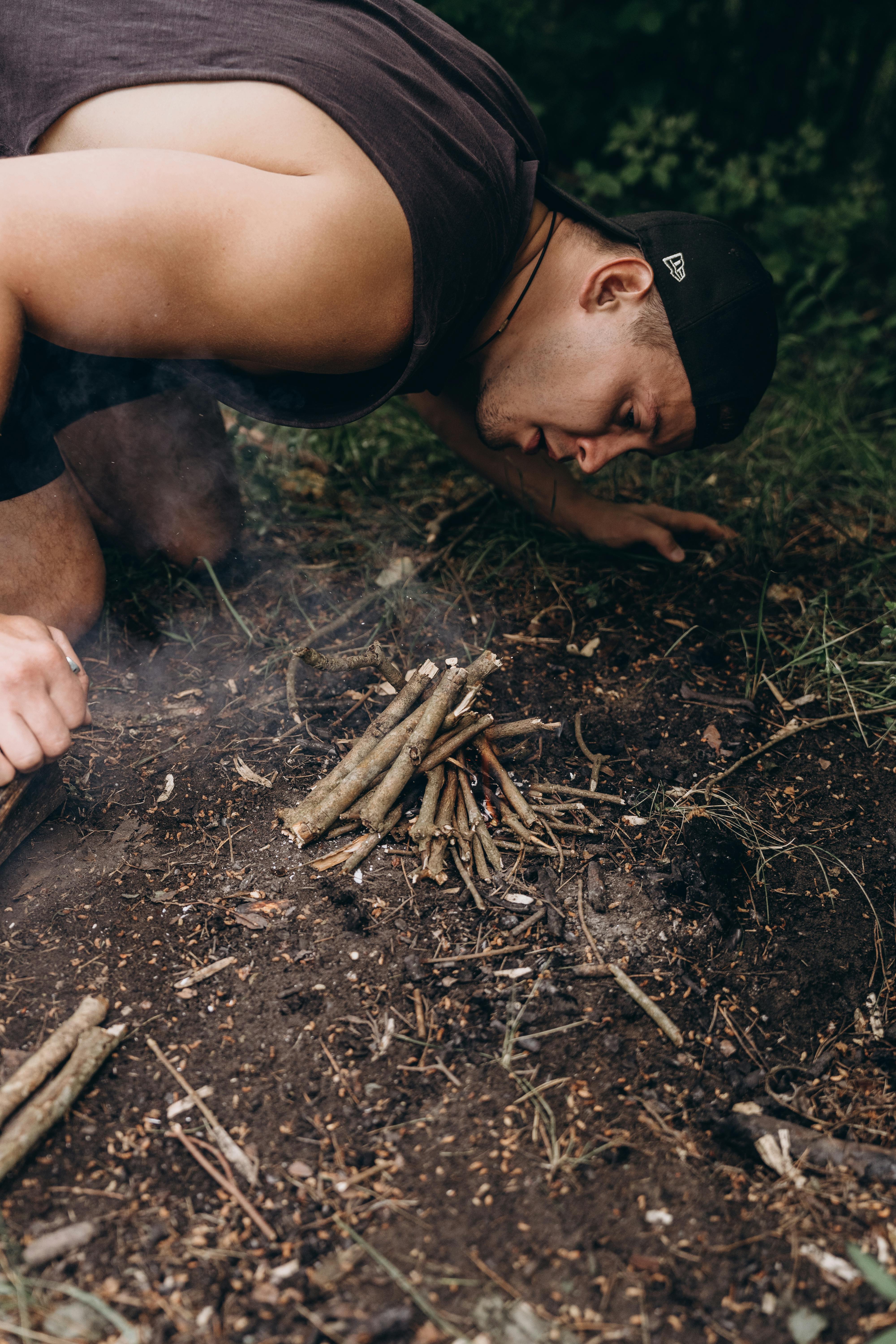 Man Starting Campfire in Forest Setting · Free Stock Photo