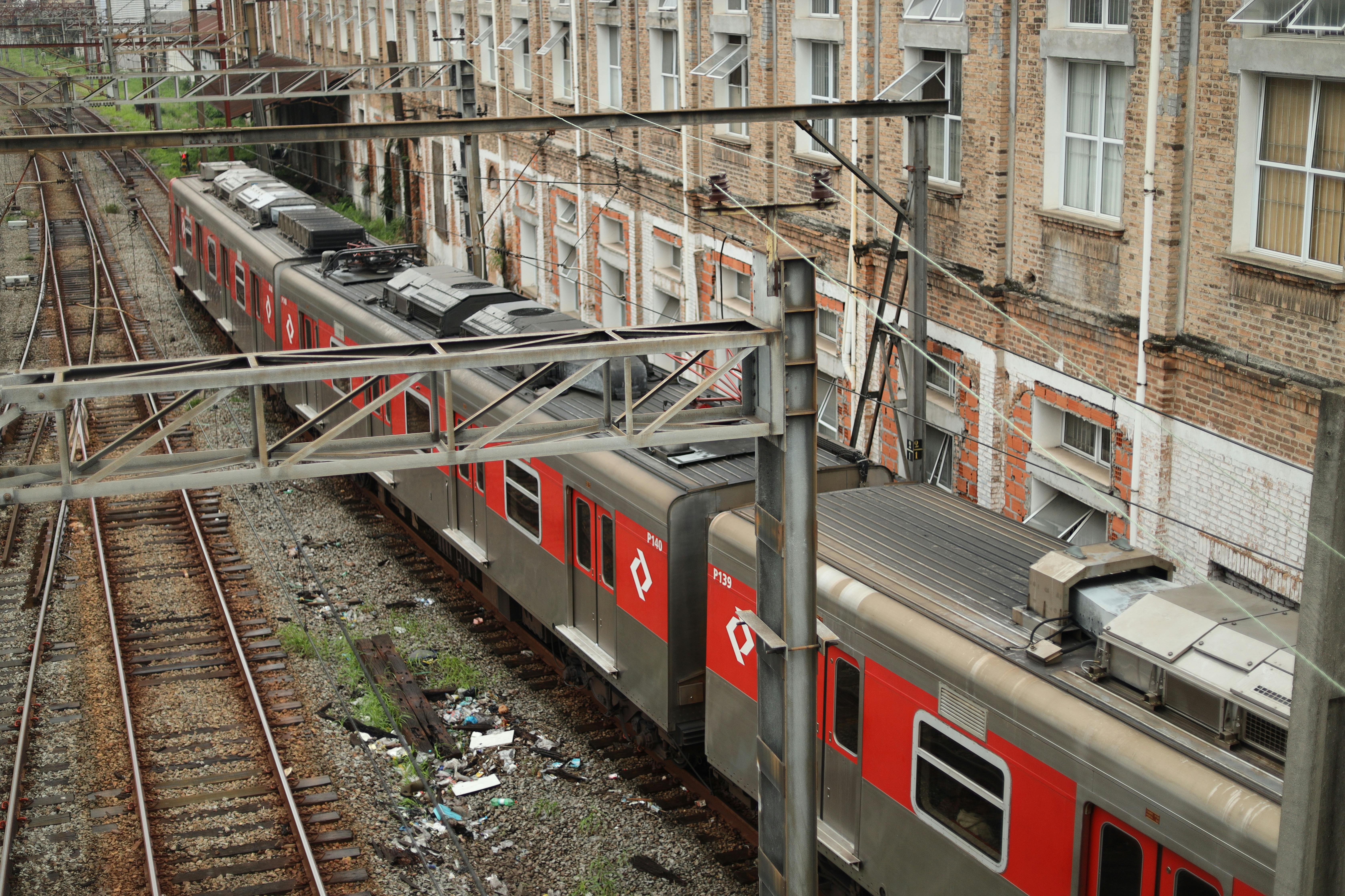 Red train passing through urban railway tracks · Free Stock Photo