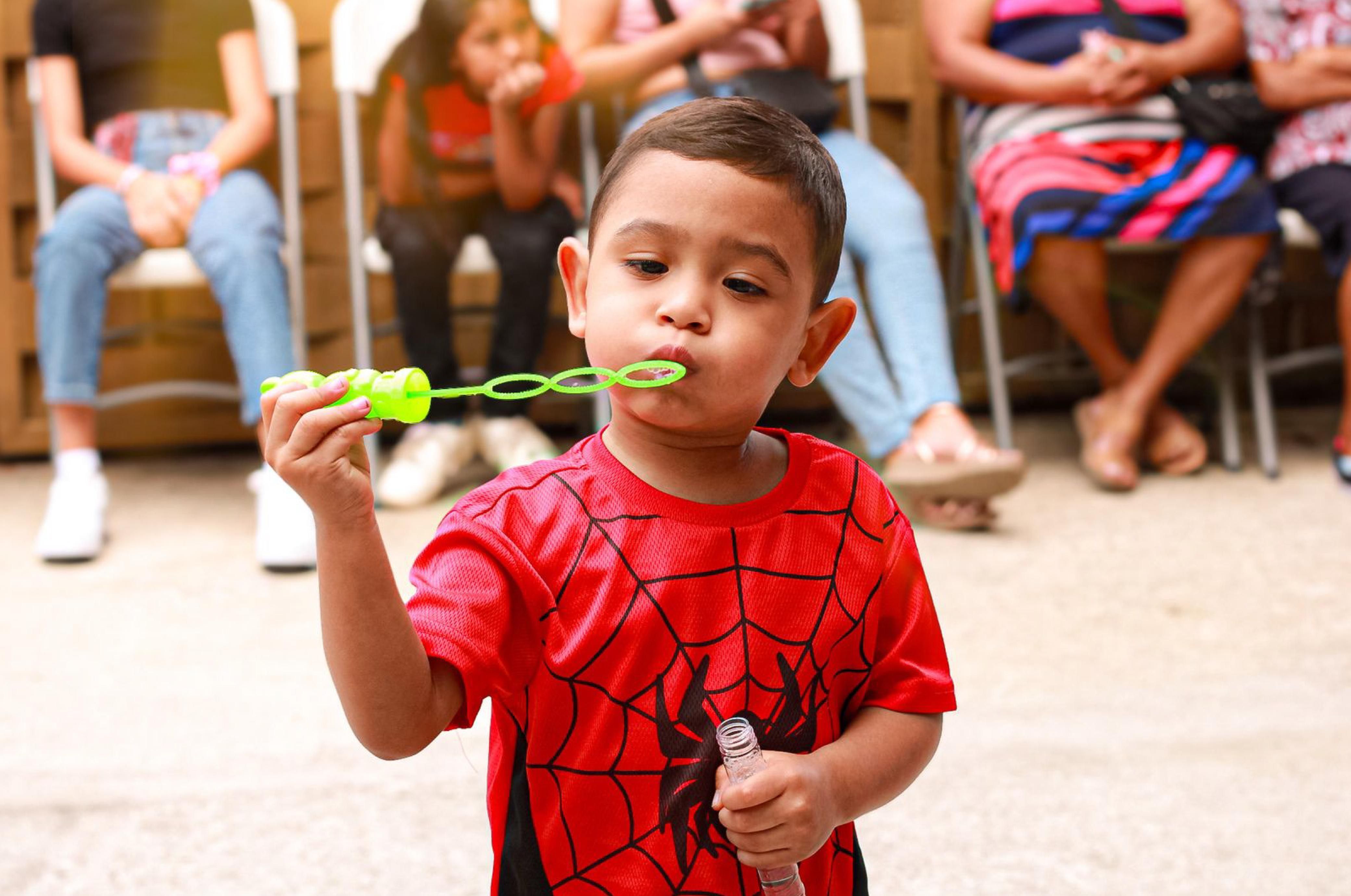 Young Boy Blowing Bubbles at Outdoor Event · Free Stock Photo