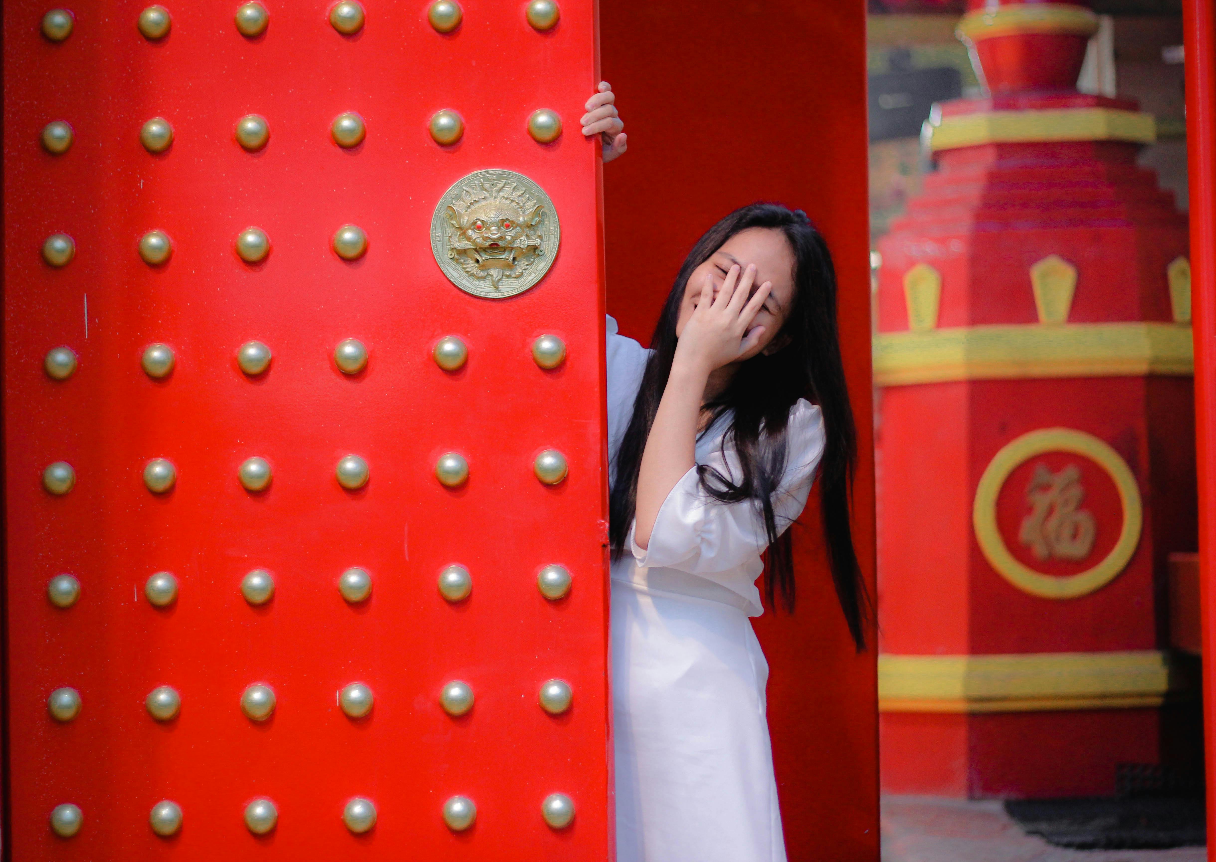 Woman Peeking and Smiling Behind Red Door · Free Stock Photo