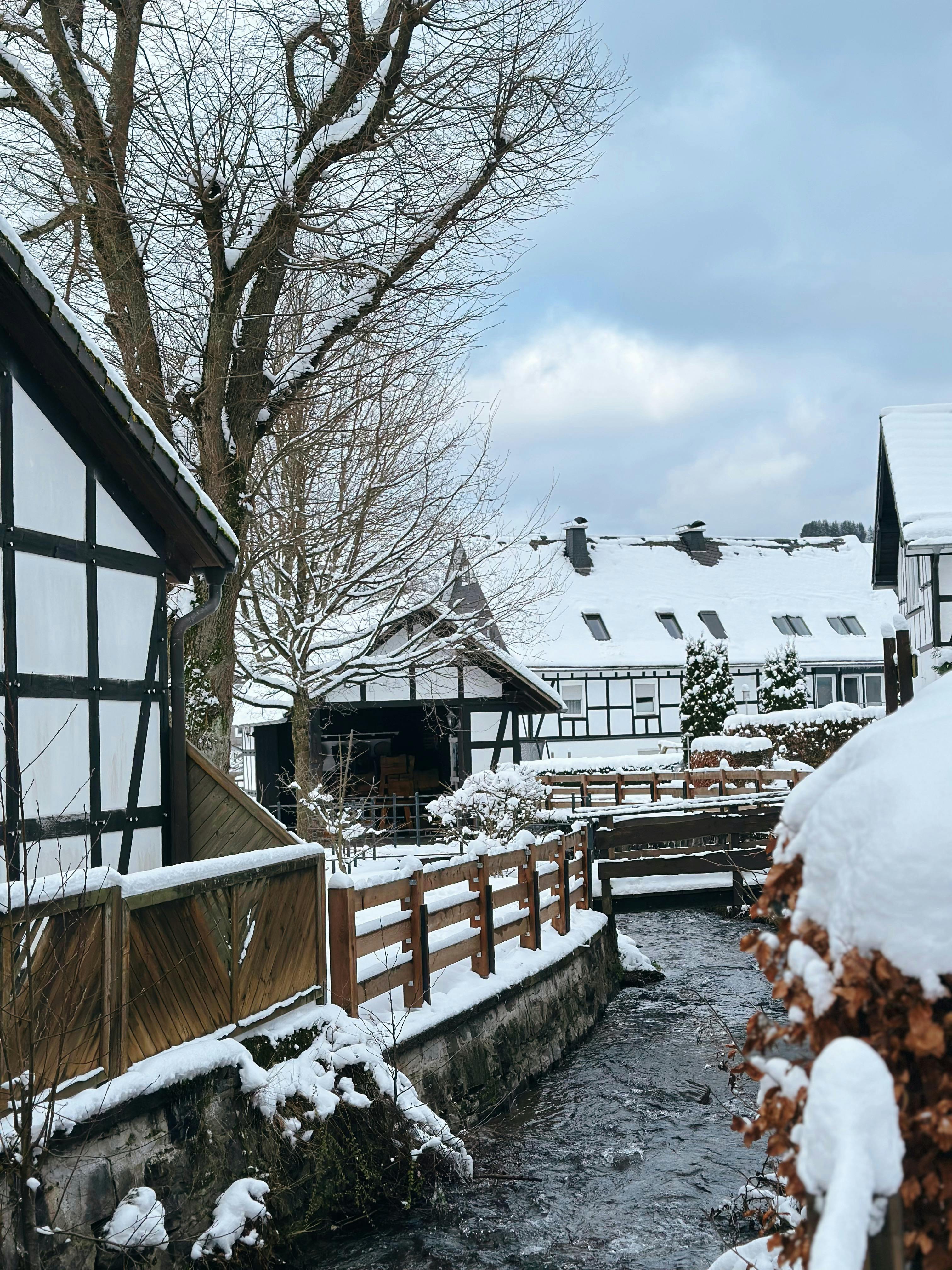 Charming Snowy Village with Stream and Timber Houses · Free Stock Photo