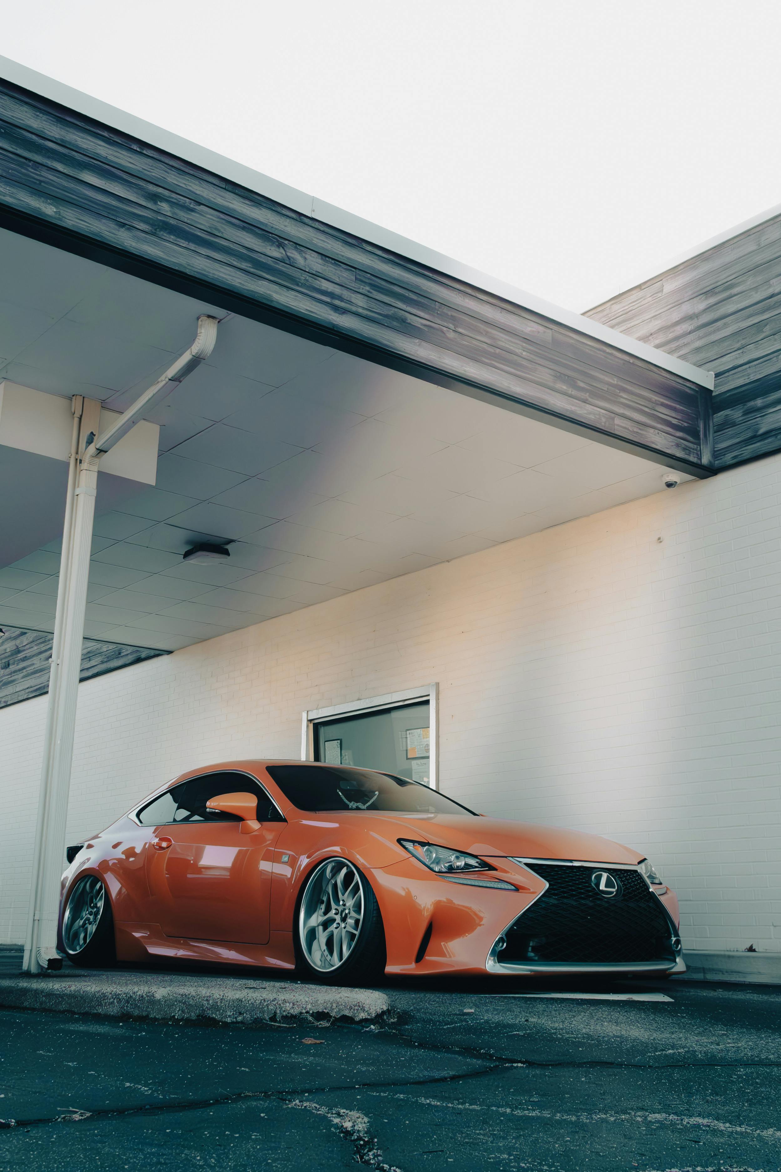 Sleek Orange Lexus Stance Car Under Building · Free Stock Photo