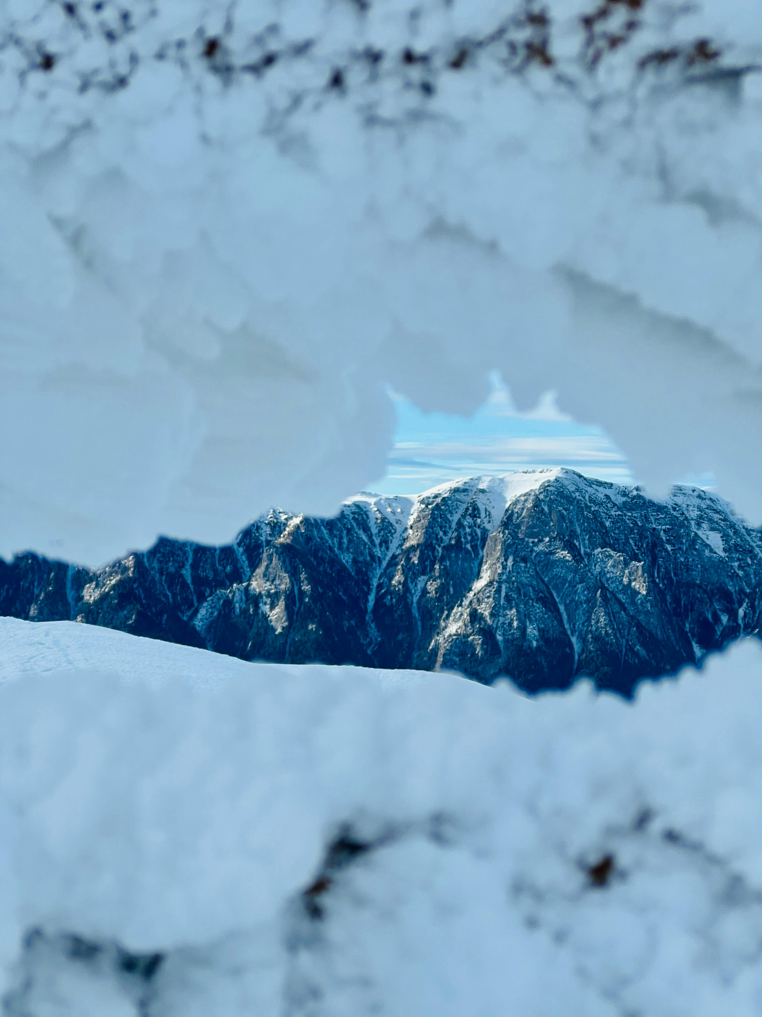 Snowy Mountain Peaks through Icy Archway · Free Stock Photo