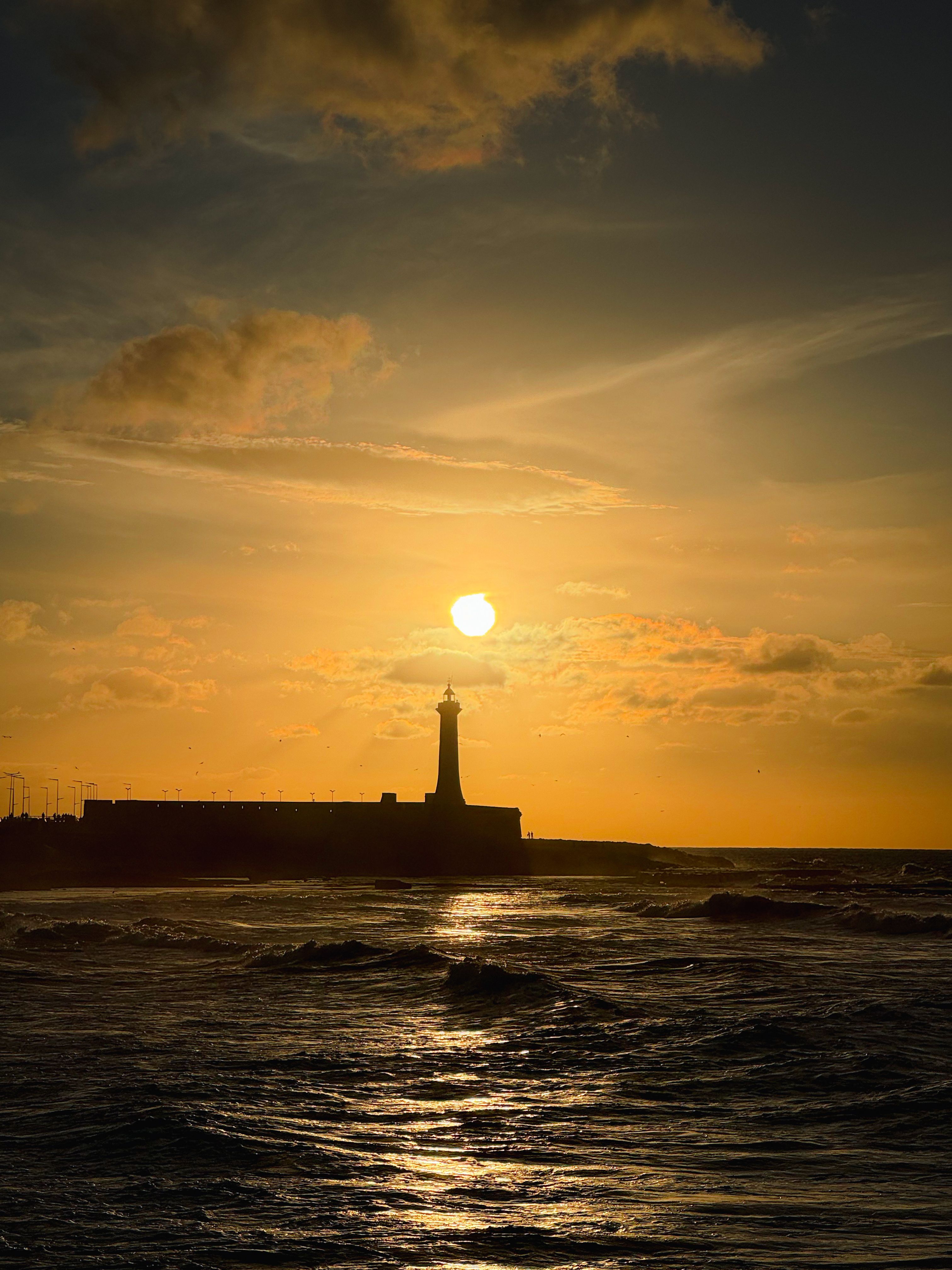 Dramatic Lighthouse Sunset Over Ocean Waves · Free Stock Photo