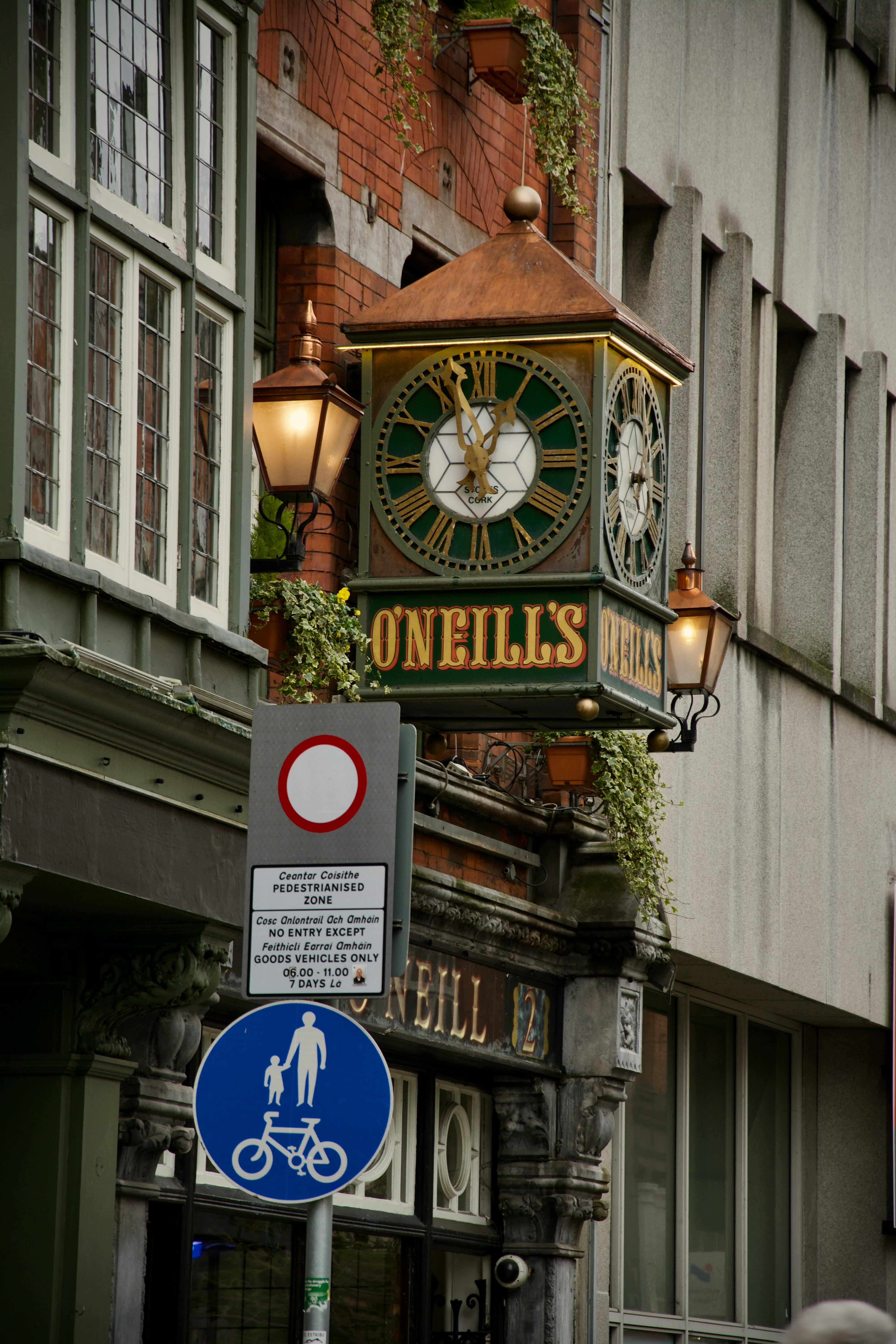 Vintage Clock Signage on Irish Pub in Urban Setting · Free Stock Photo
