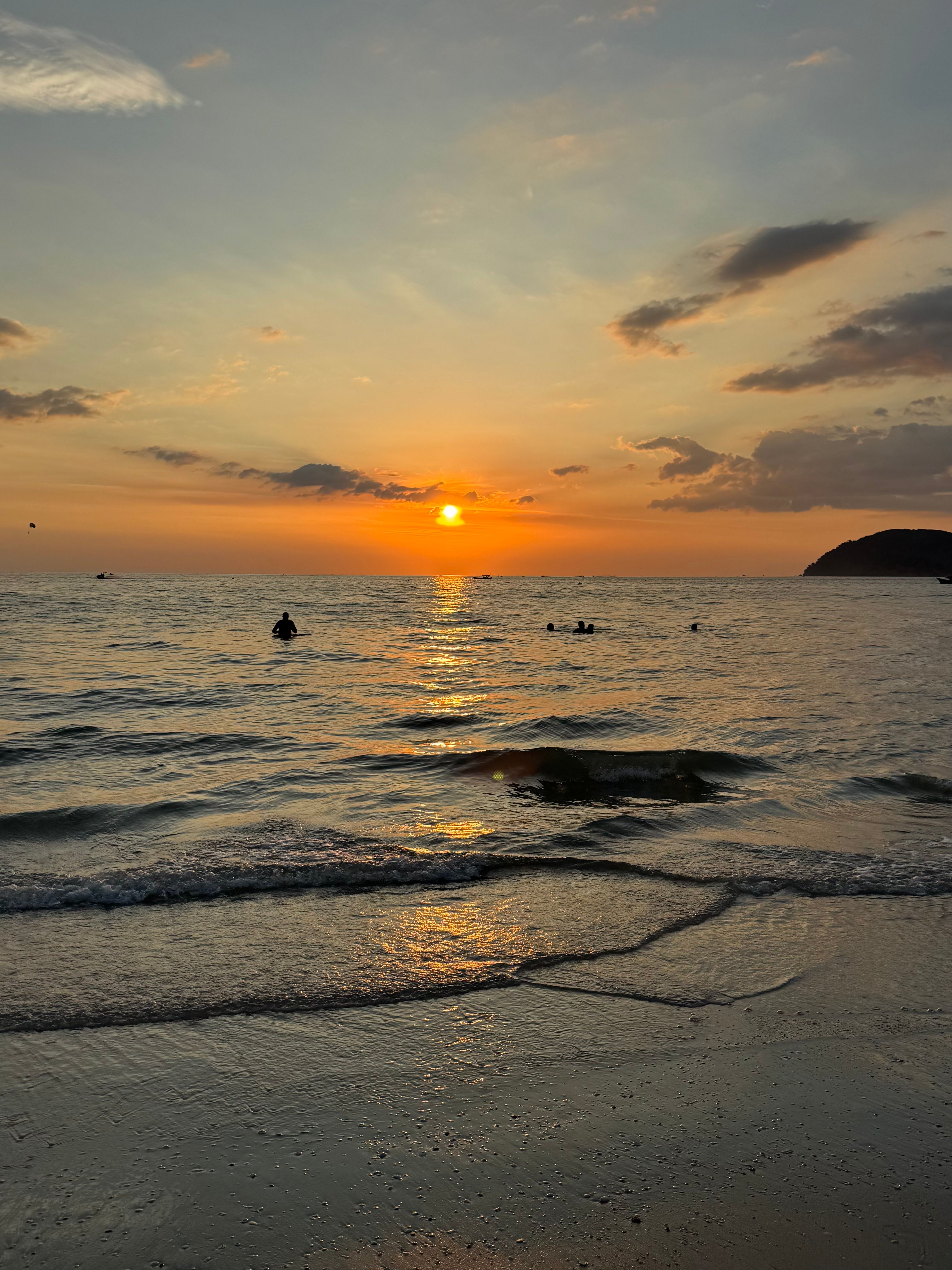 Scenic Beach Sunset with Silhouetted Swimmers · Free Stock Photo