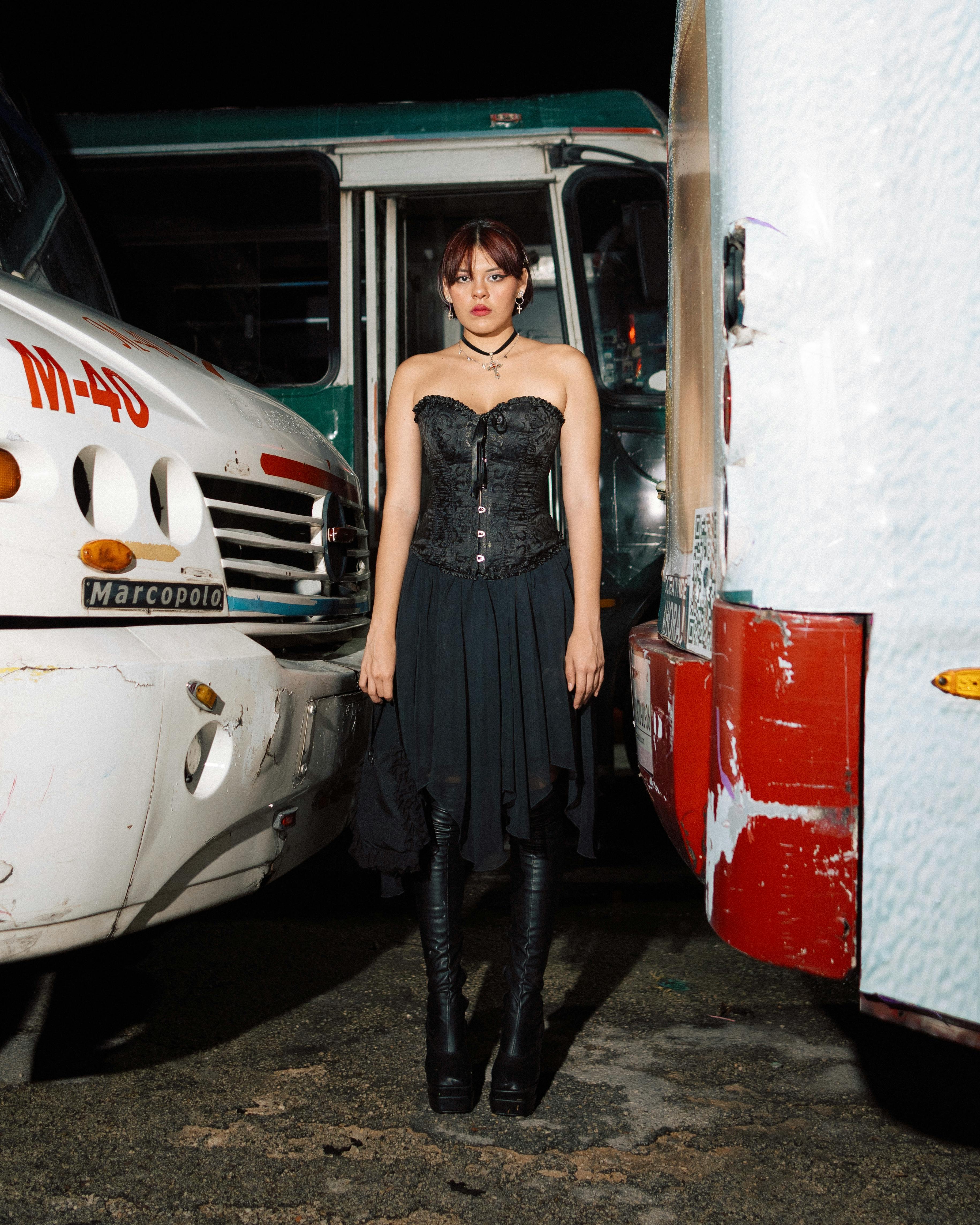 Woman in Goth Fashion Between Buses at Night · Free Stock Photo