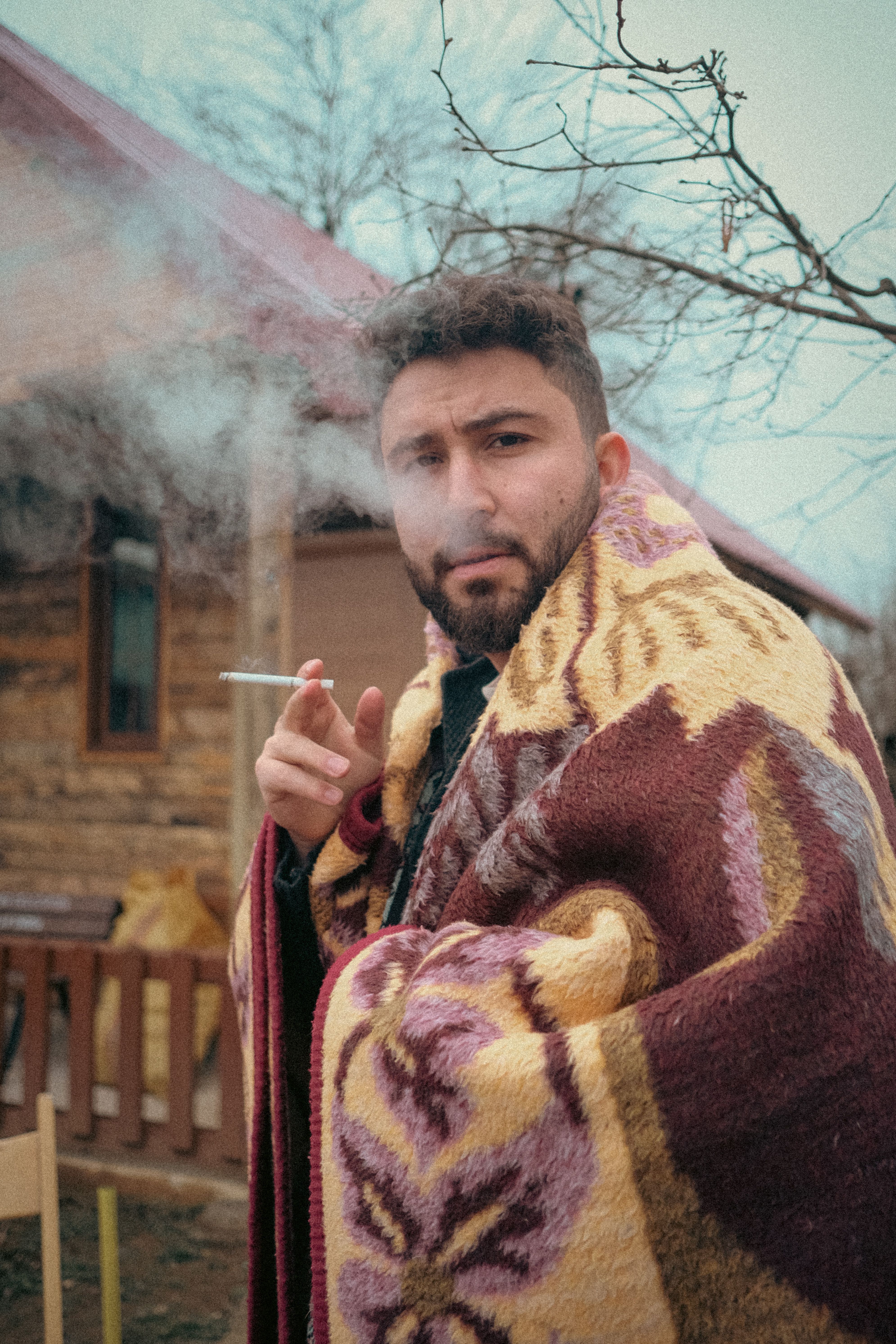Man Wrapped in Blanket Smoking Outdoors · Free Stock Photo