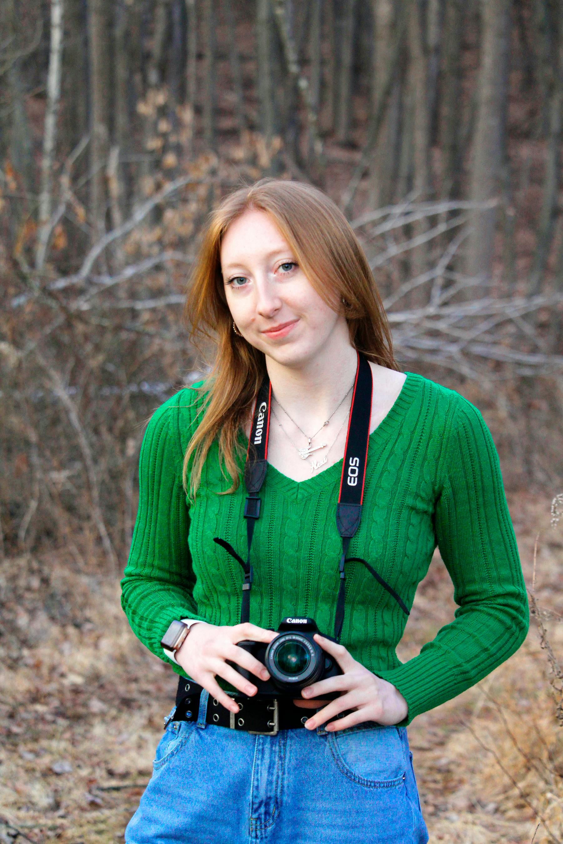 Young Woman Holding Camera in Forest Setting · Free Stock Photo