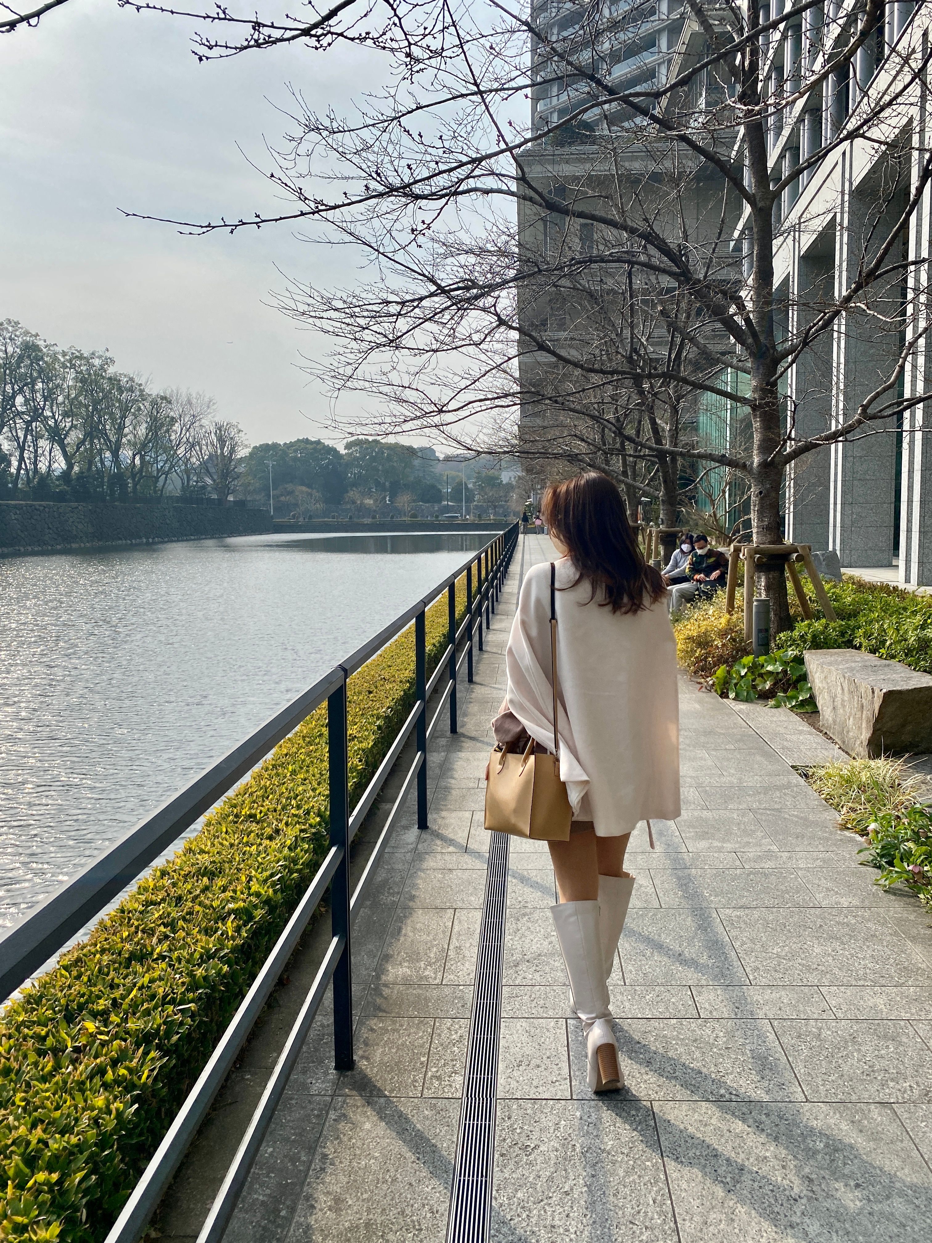 Chic Woman Walking Along Riverside Path in City · Free Stock Photo