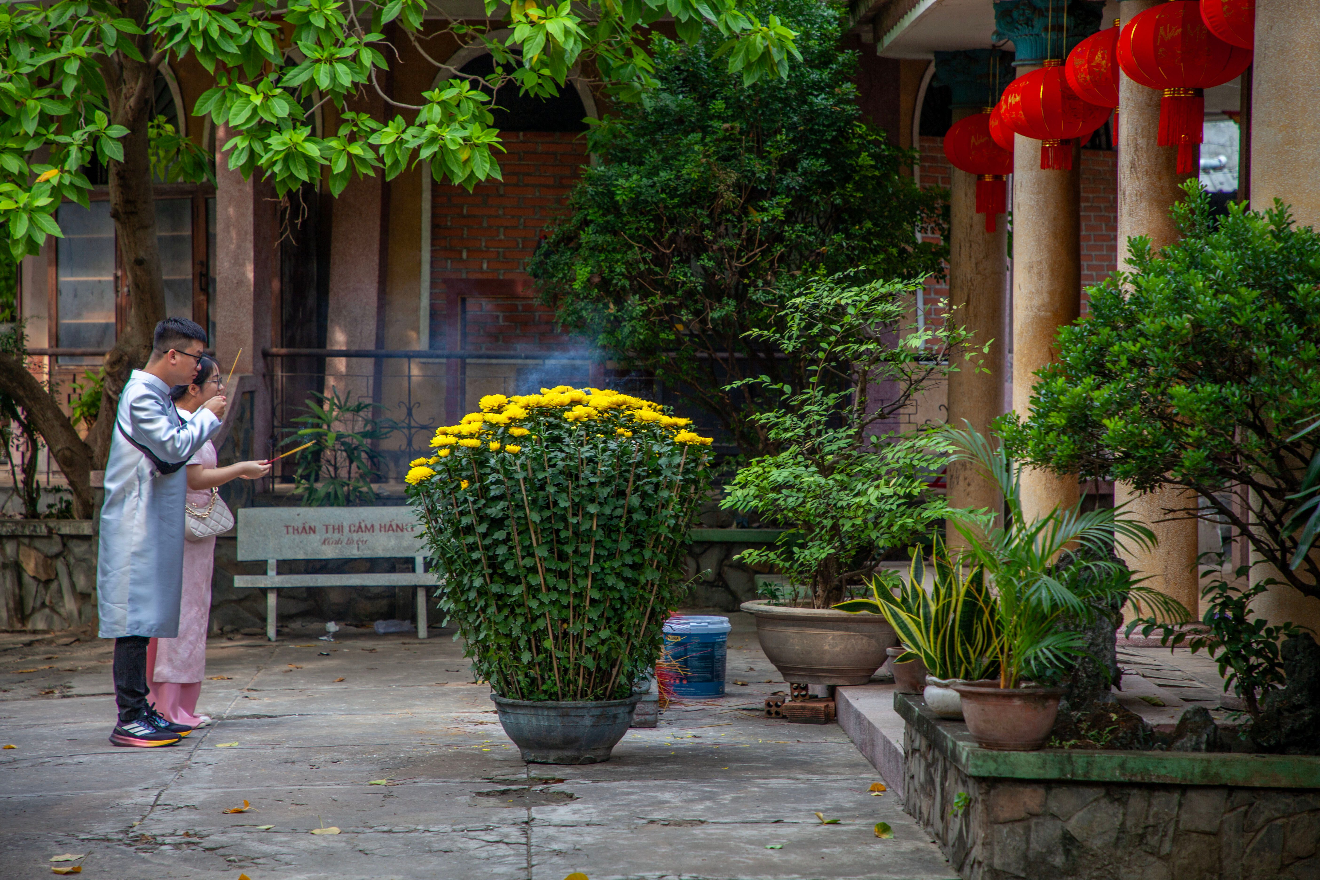 Asian couple performing prayer ritual in temple courtyard · Free Stock ...