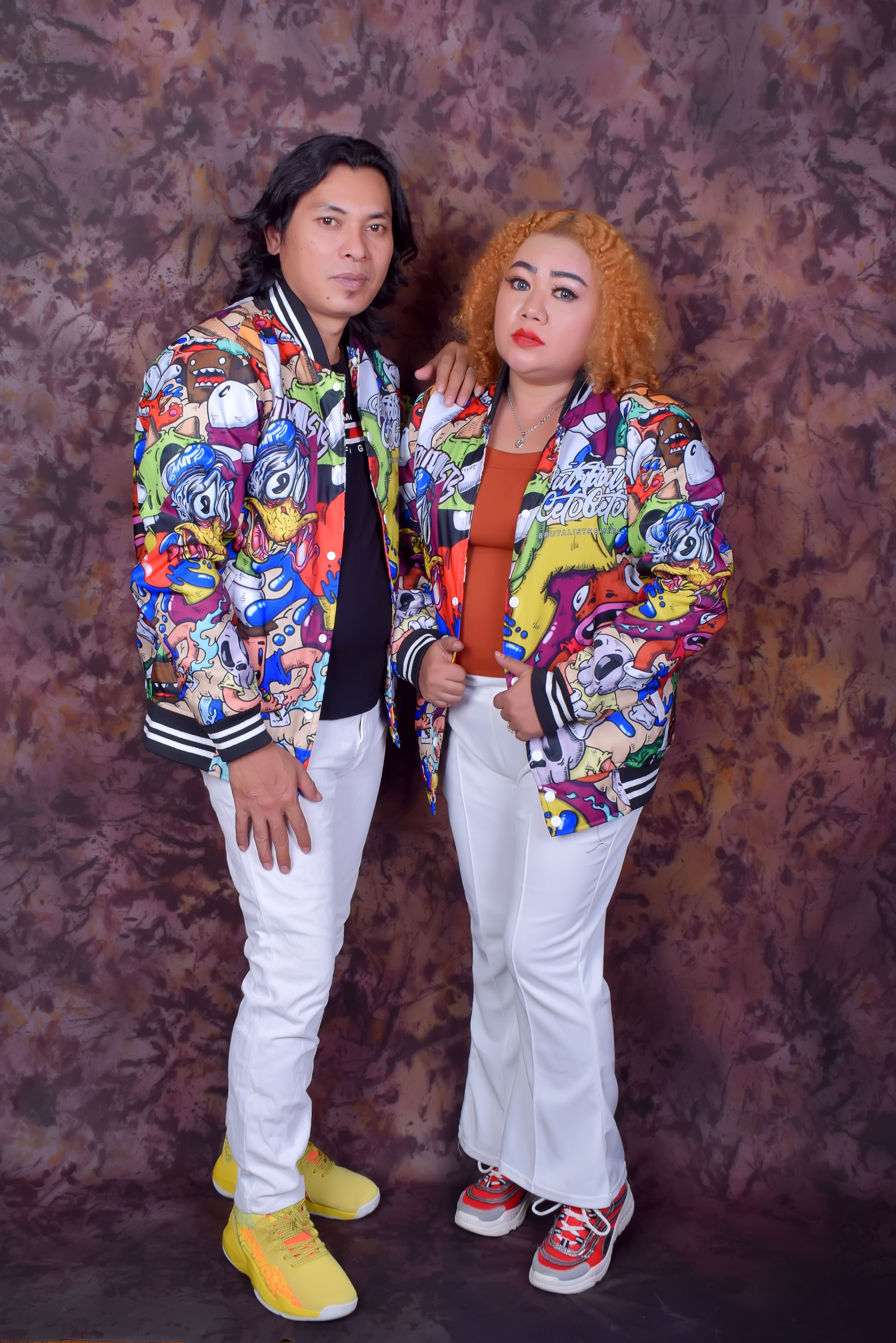 Colorful Couple in Matching Graphic Jackets Indoors · Free Stock Photo
