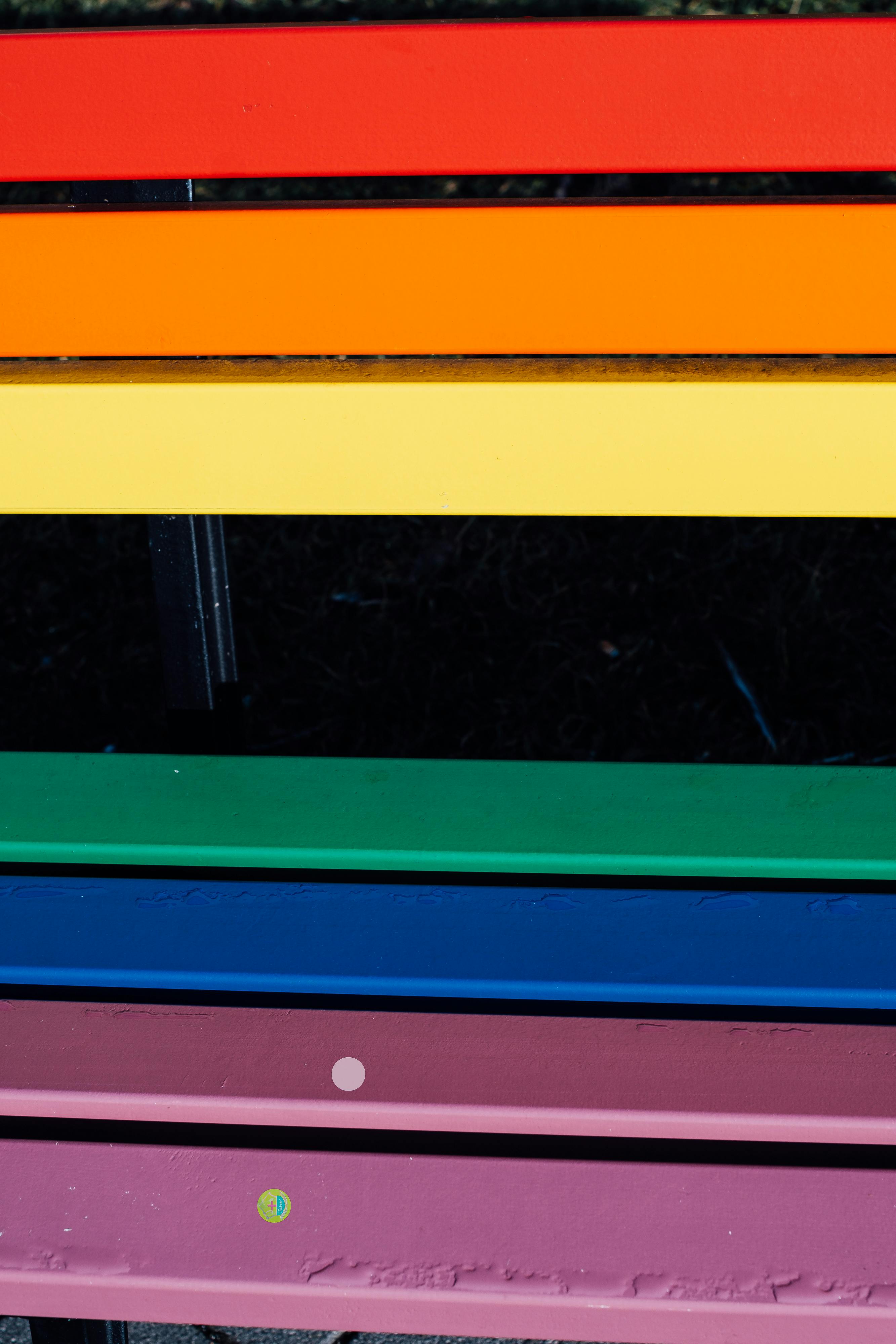 Vibrant Rainbow Striped Park Bench in Garden · Free Stock Photo