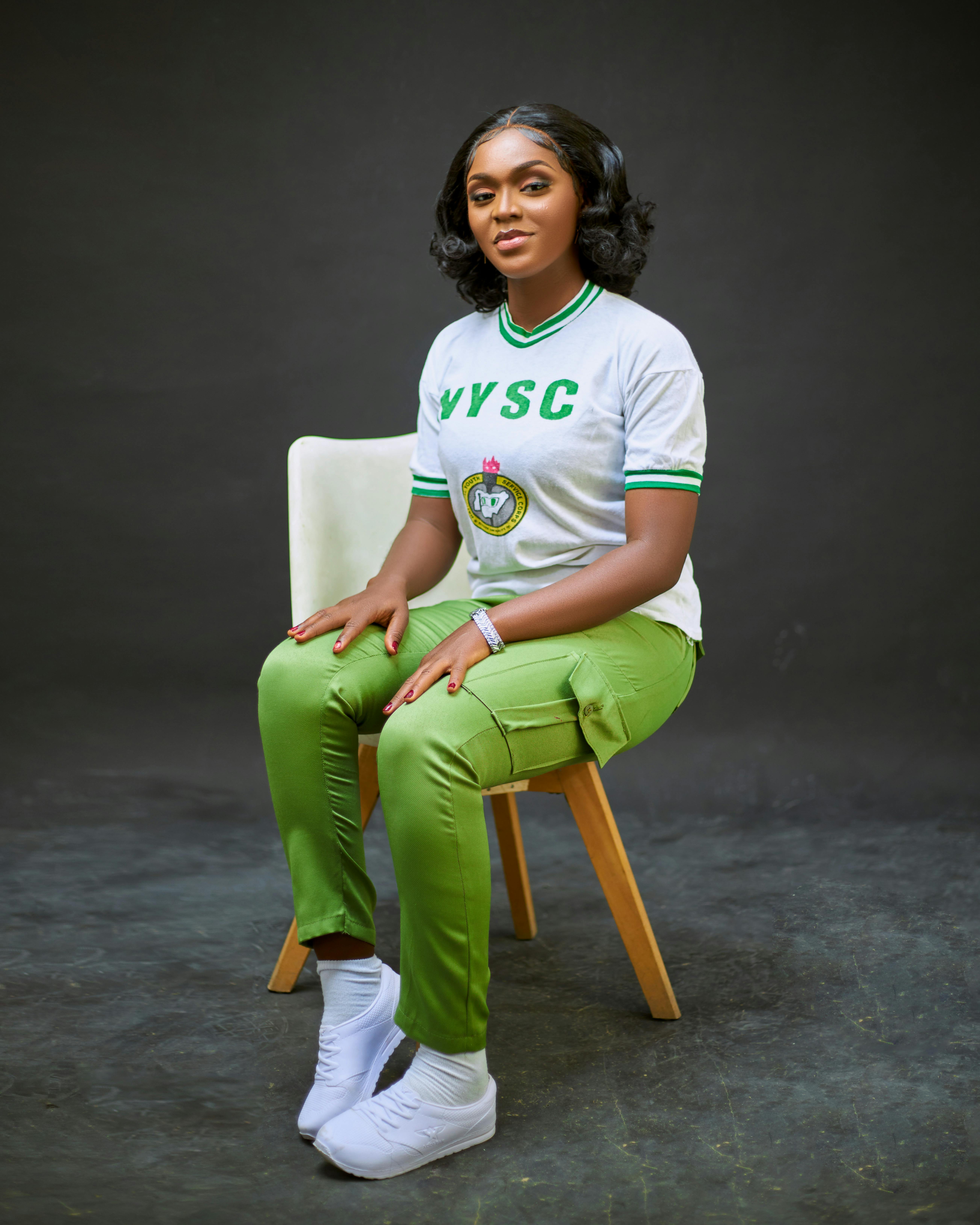 Woman in NYSC Uniform Seated on Chair · Free Stock Photo
