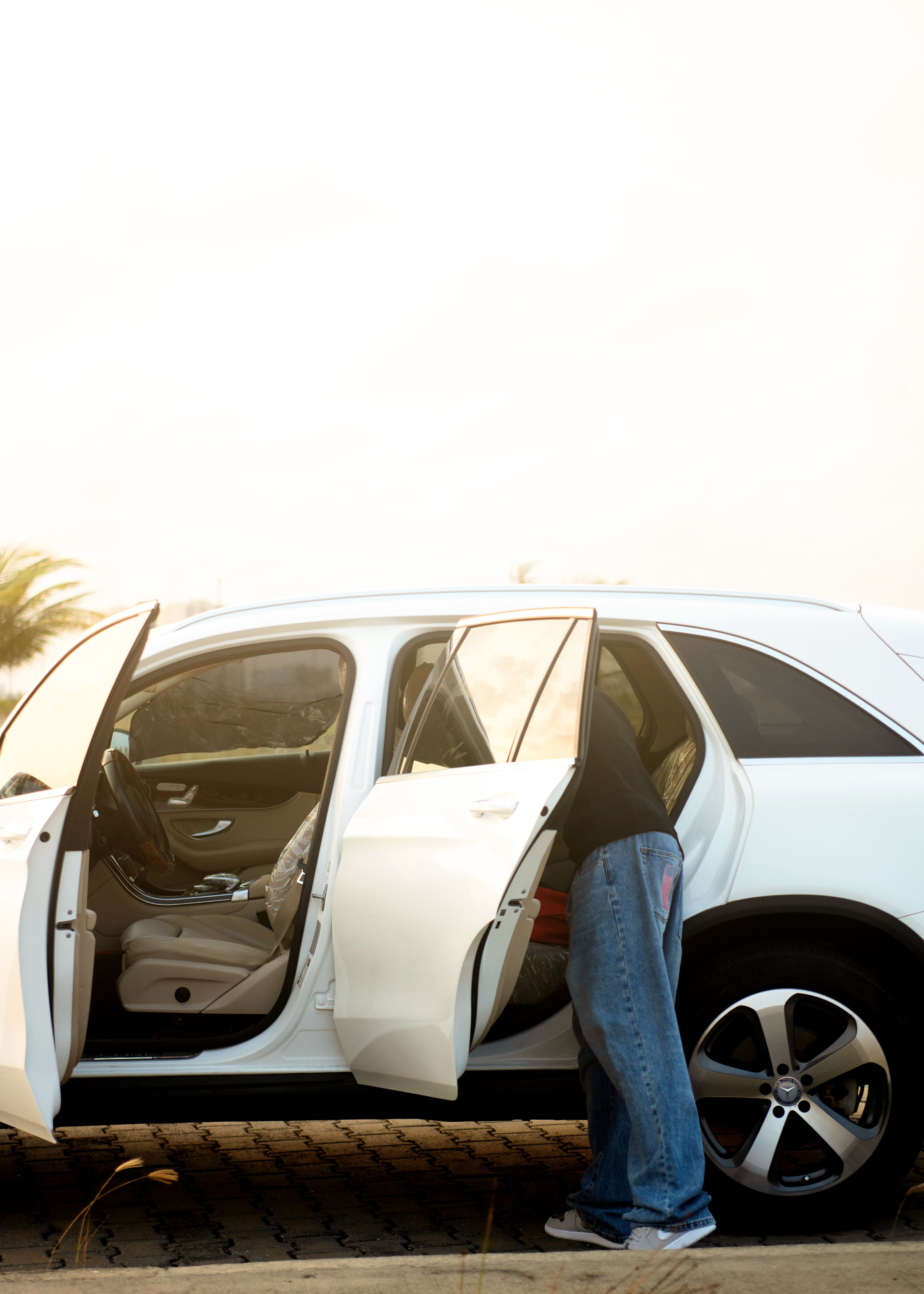 Person Searching Inside Car in Sunlit Setting · Free Stock Photo