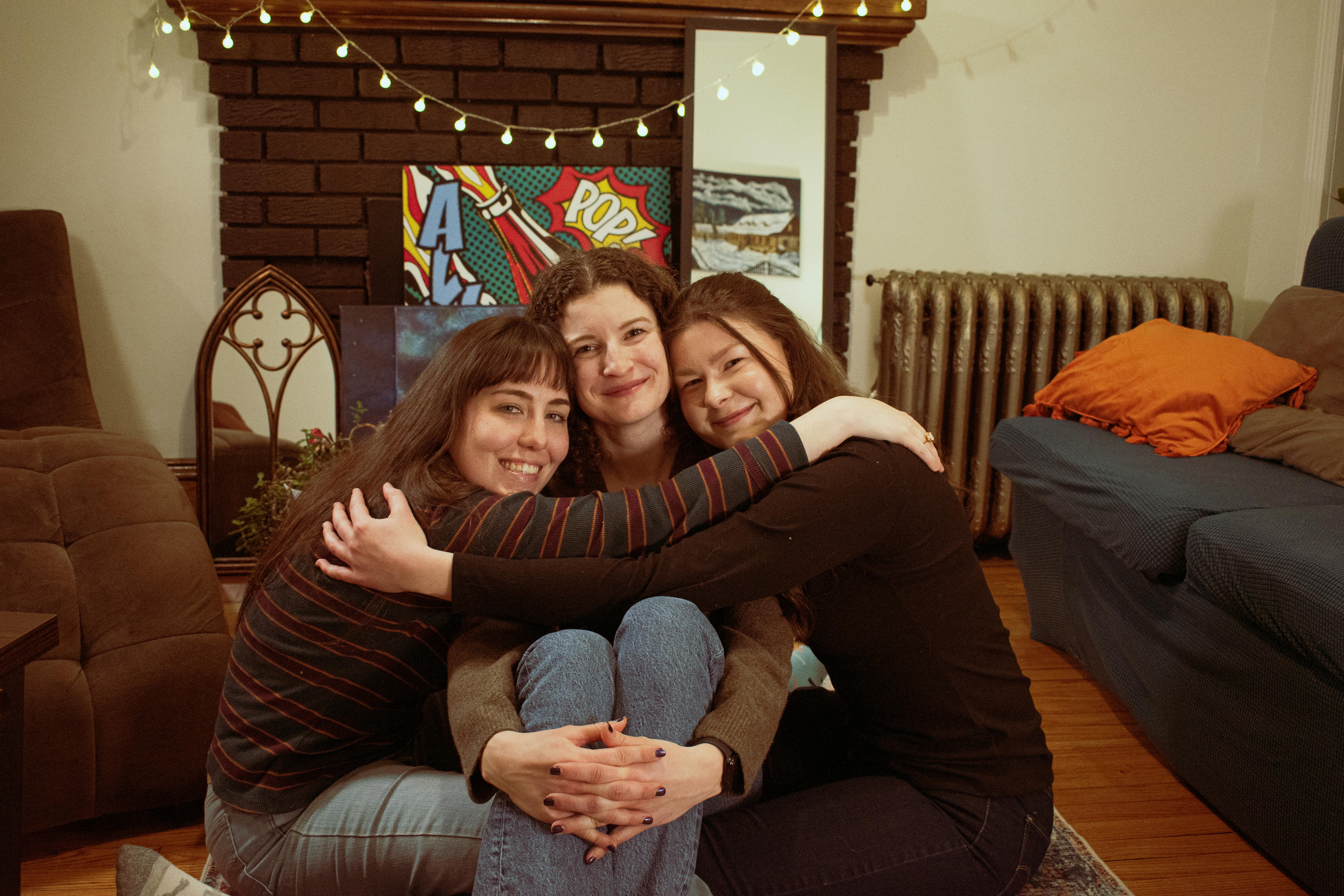 Three Friends Hugging Indoors in Warm Setting · Free Stock Photo