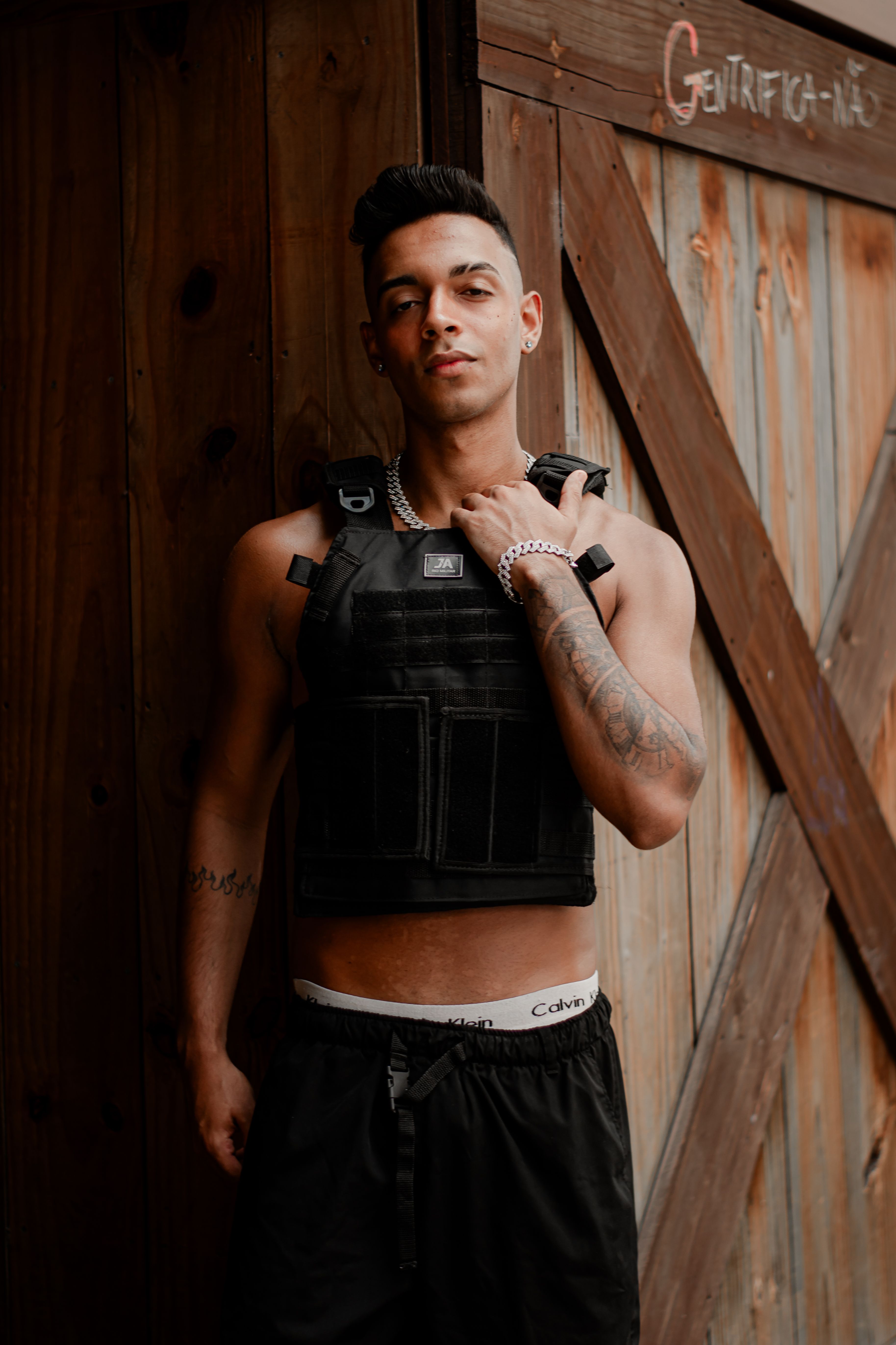 Confident Young Man in Tactical Vest by Wooden Wall · Free Stock Photo