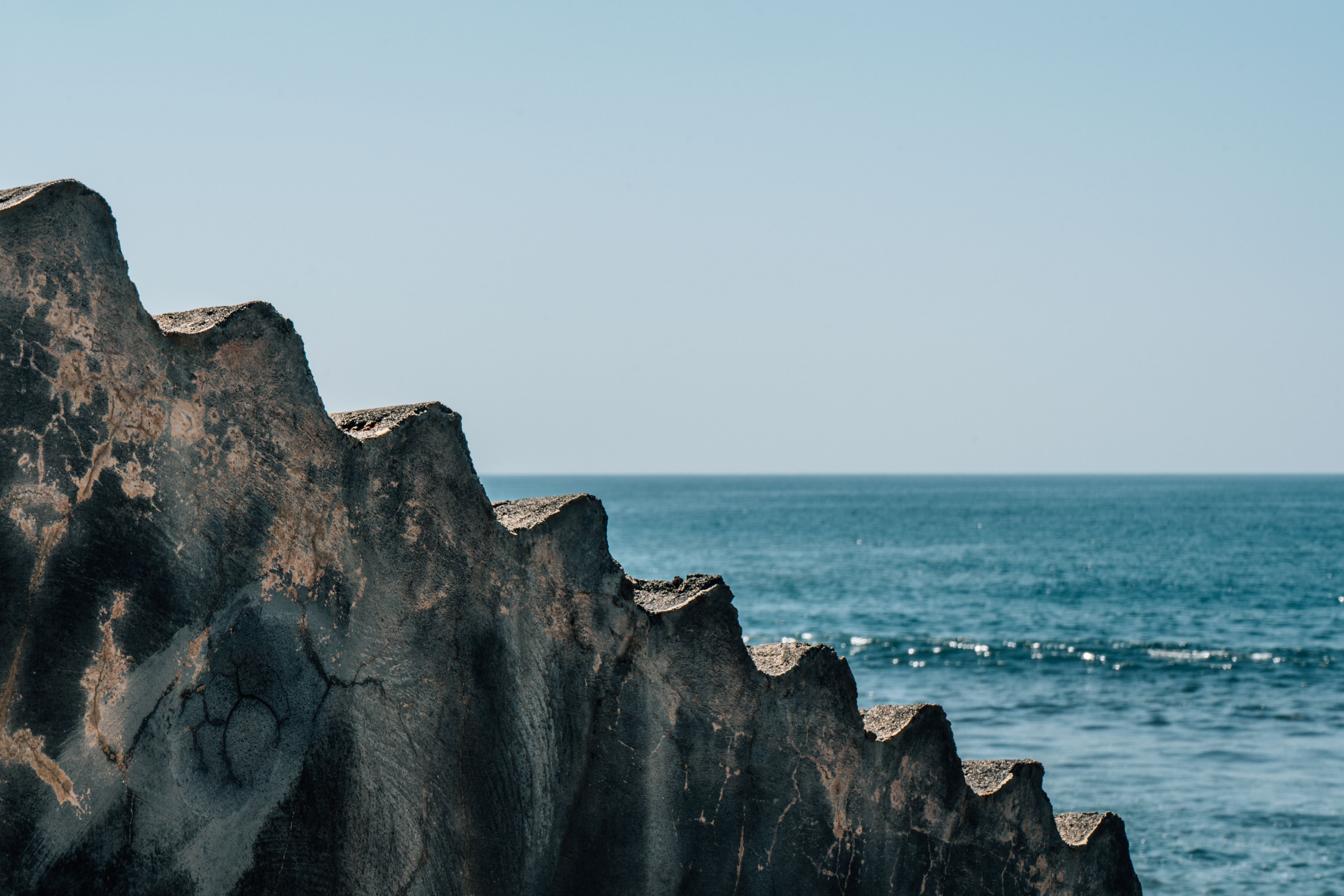 Serrated Rock Edge Against Blue Ocean Backdrop · Free Stock Photo