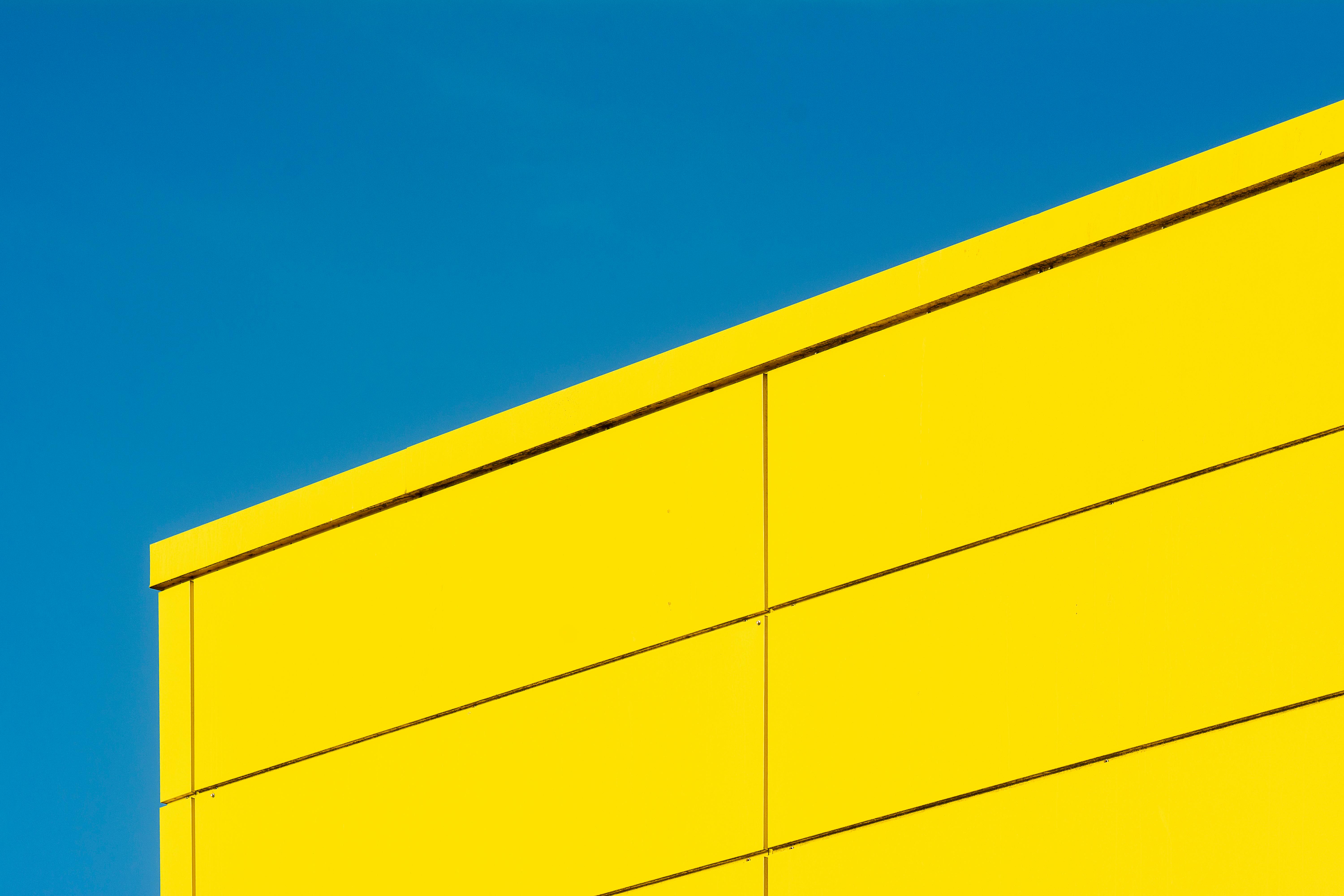 Bright Yellow Building Facade Against Blue Sky · Free Stock Photo