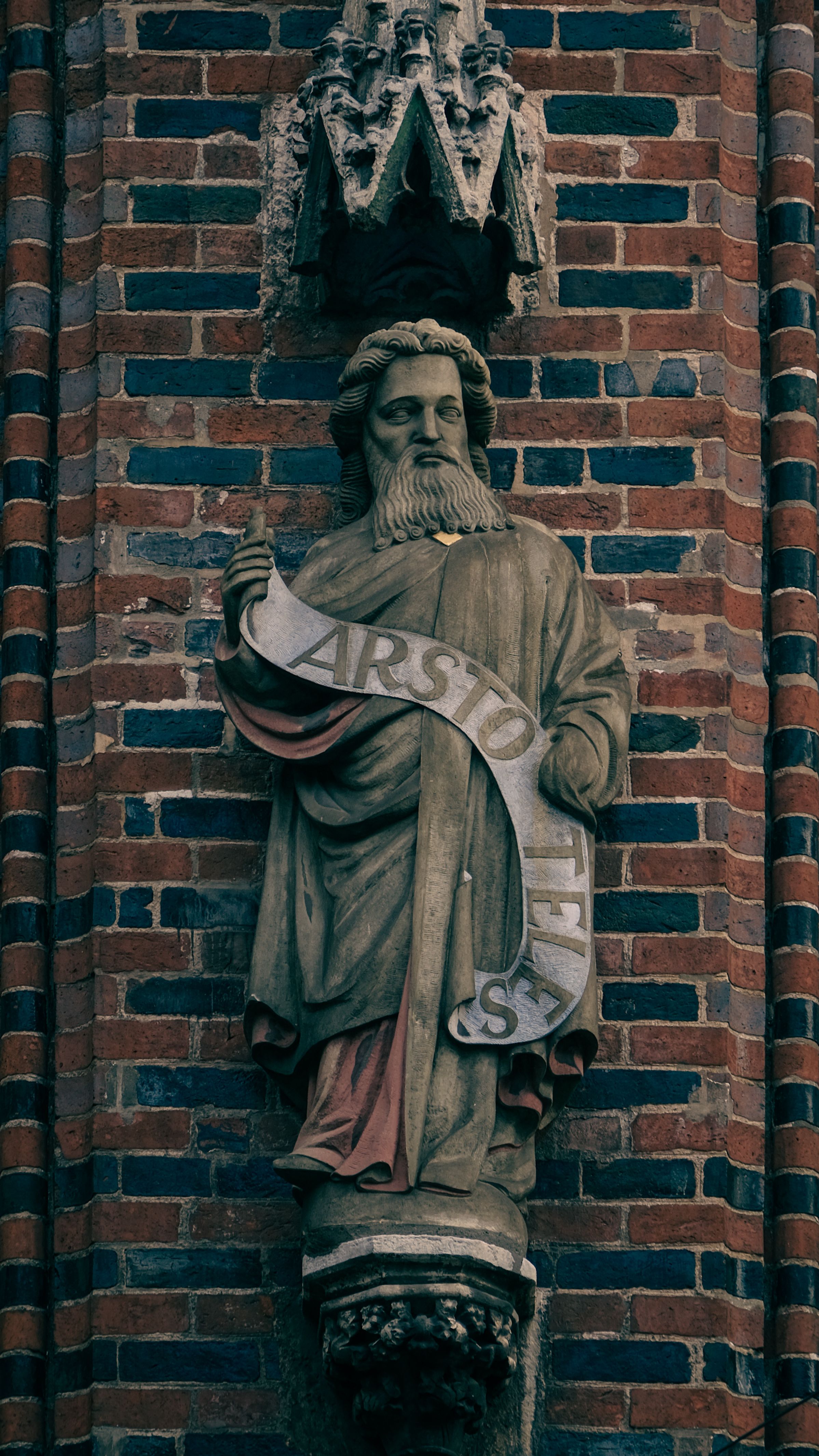 Statue of Philosopher Against Brick Wall · Free Stock Photo