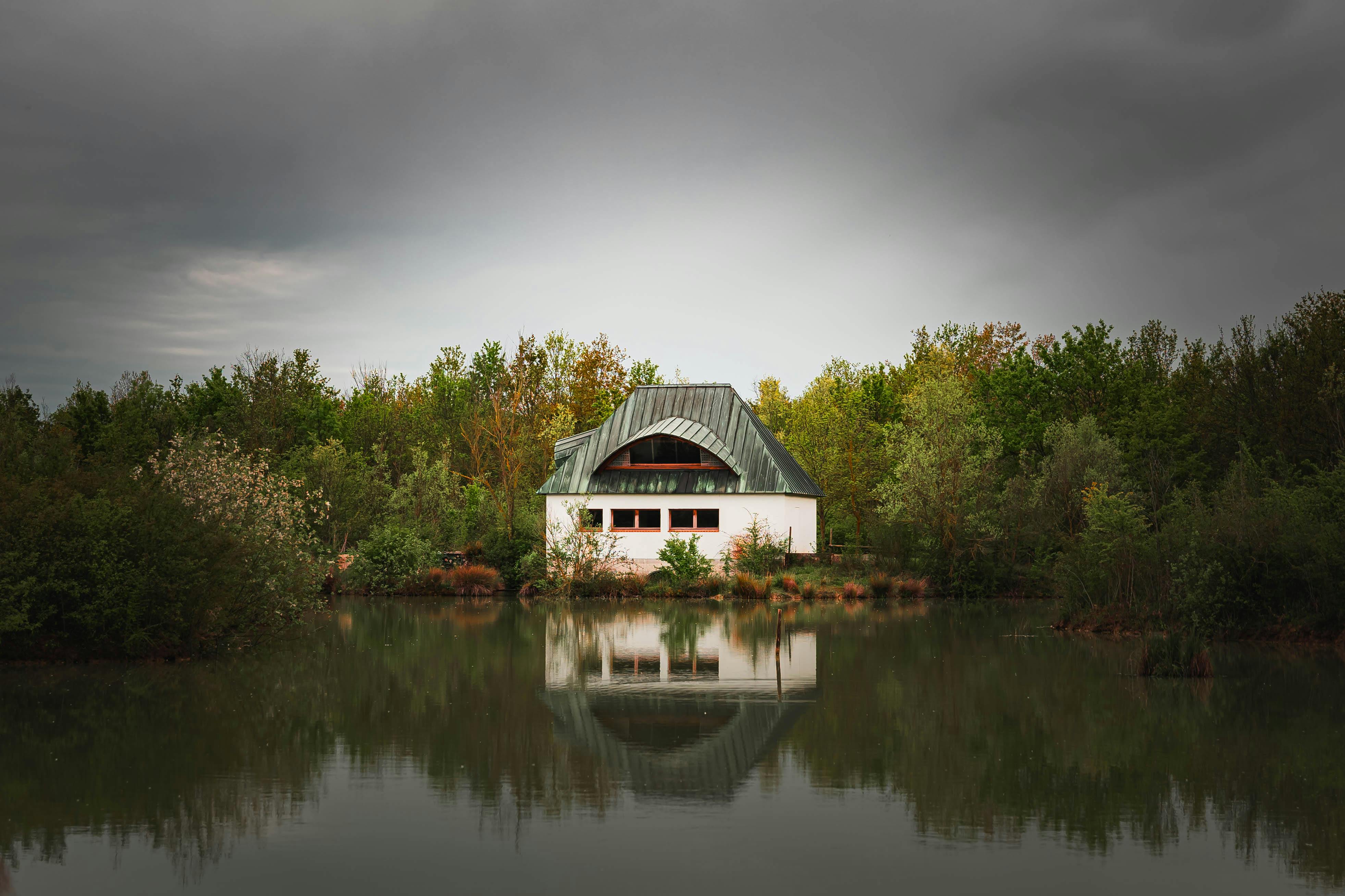 Scenic House by a Tranquil Lake Amidst Lush Greenery · Free Stock Photo