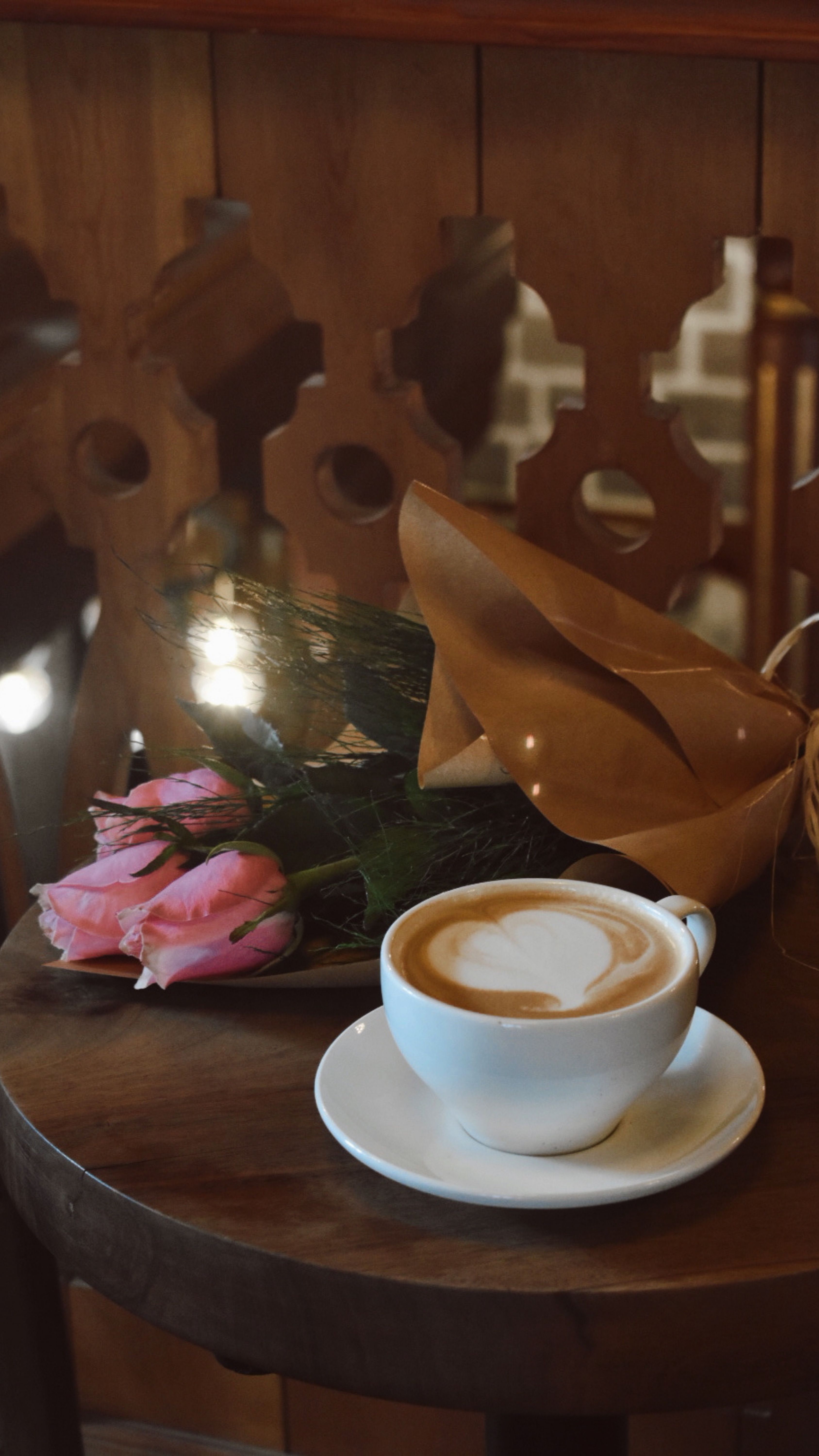 Cozy Café Setting with Cappuccino and Roses · Free Stock Photo