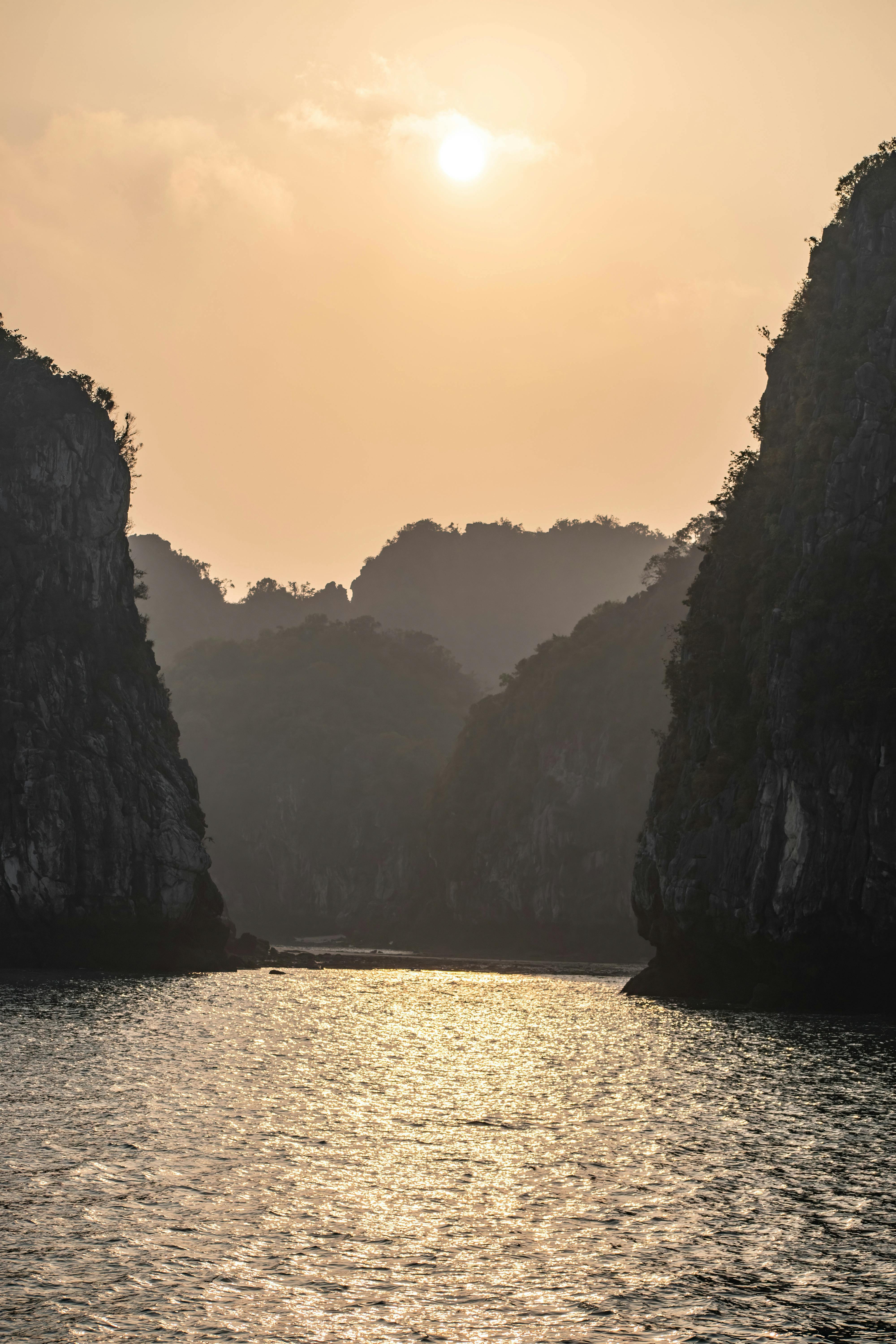 Sunset View of Karst Cliffs Over Serene Waters · Free Stock Photo